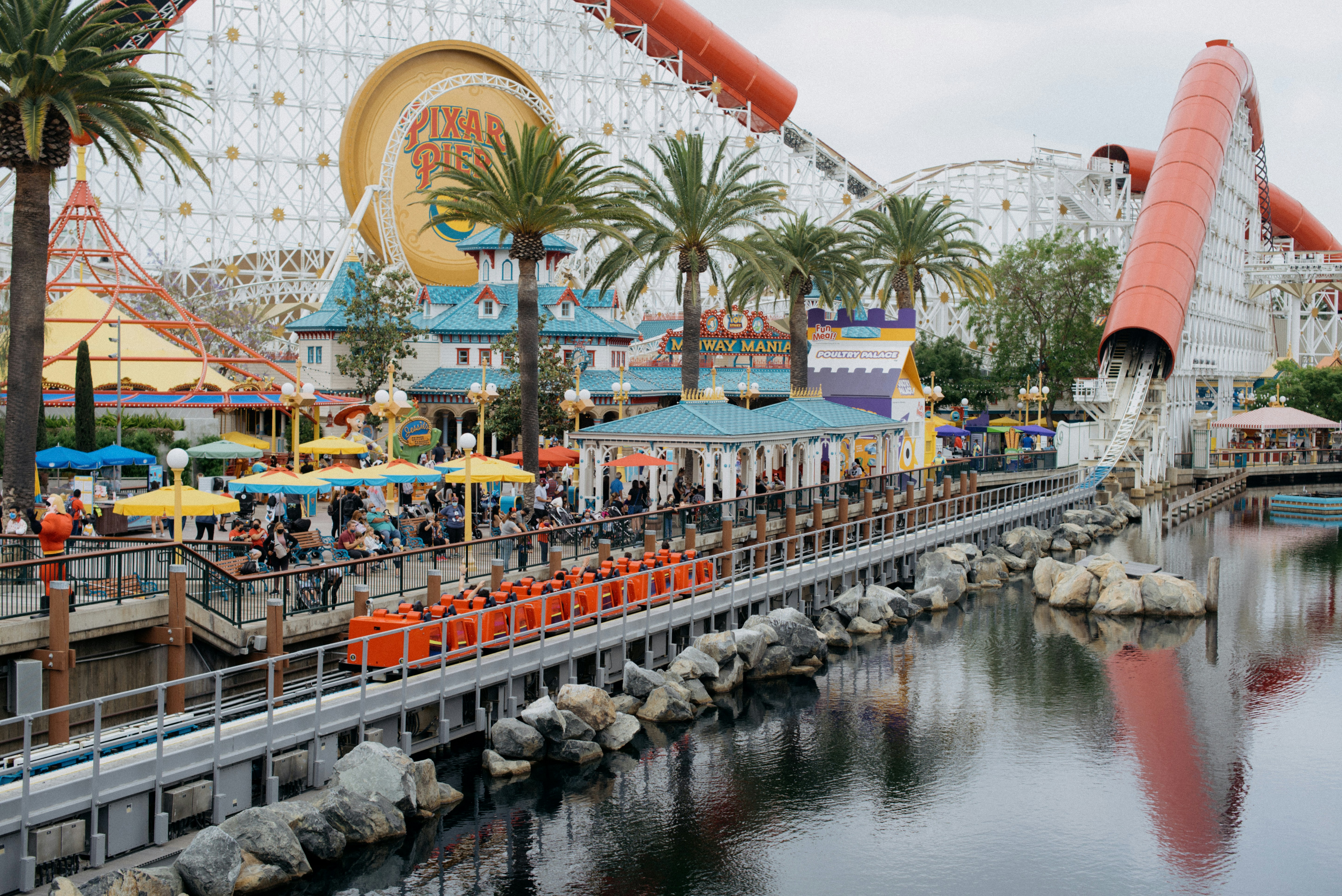 Vibrant amusement park with a roller coaster reflecting in a calm lagoon.