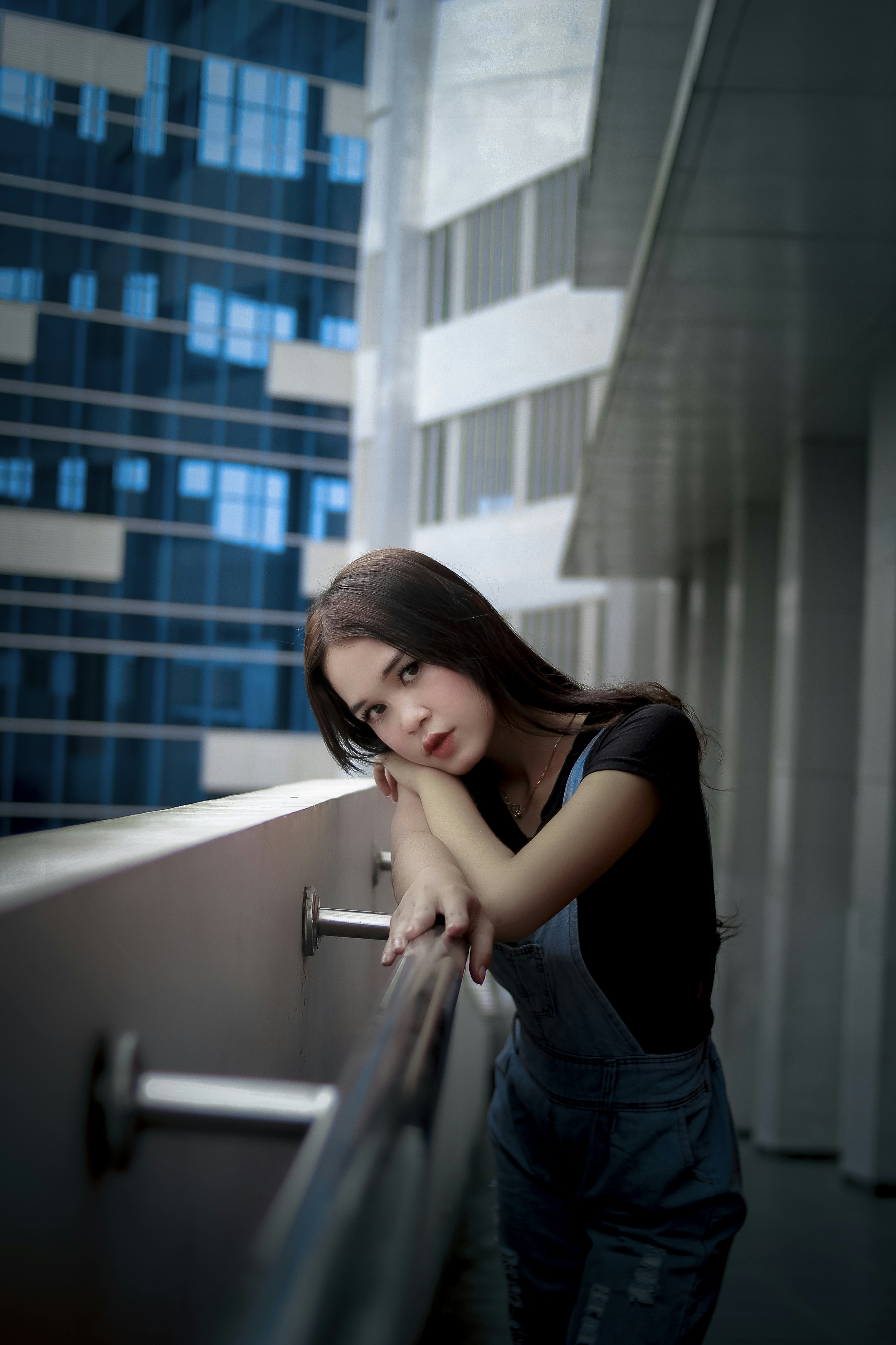 A woman leaning against a railing in front of a building photo – Free ...