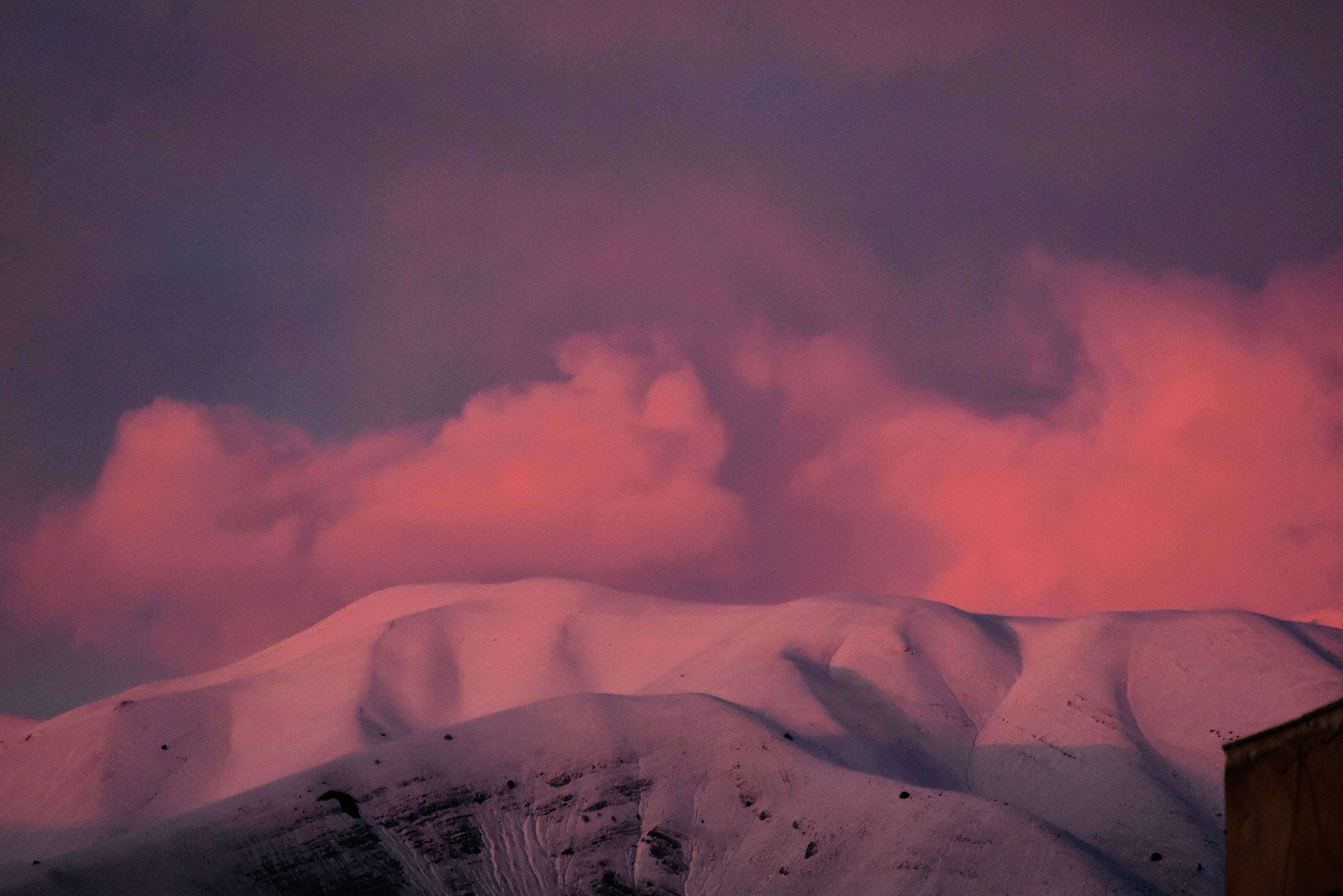Dusk on the Pink Ridge: Snow-Crowned Peaks Beneath Velvet Clouds