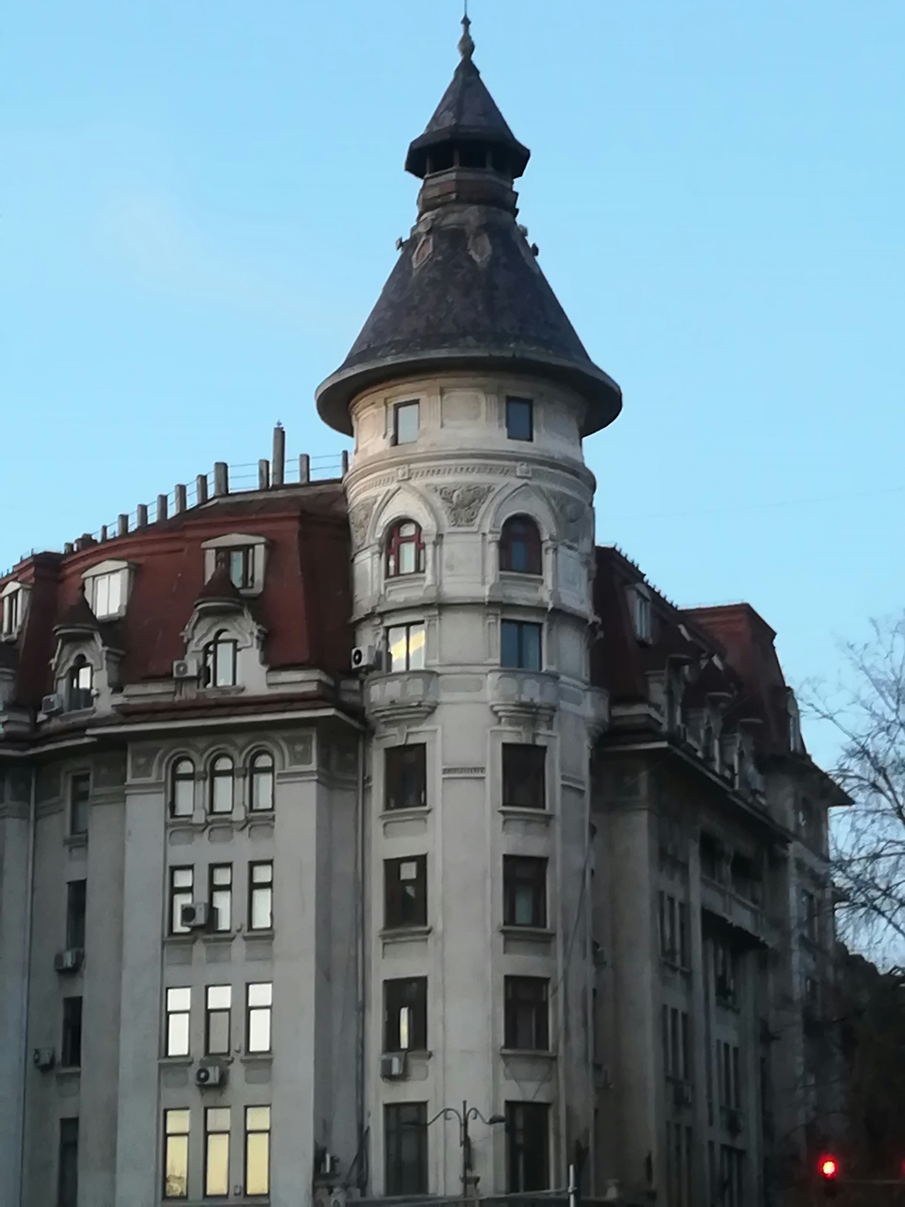 Historic building featuring a prominent turret and intricate facade details, set against a clear blue sky.