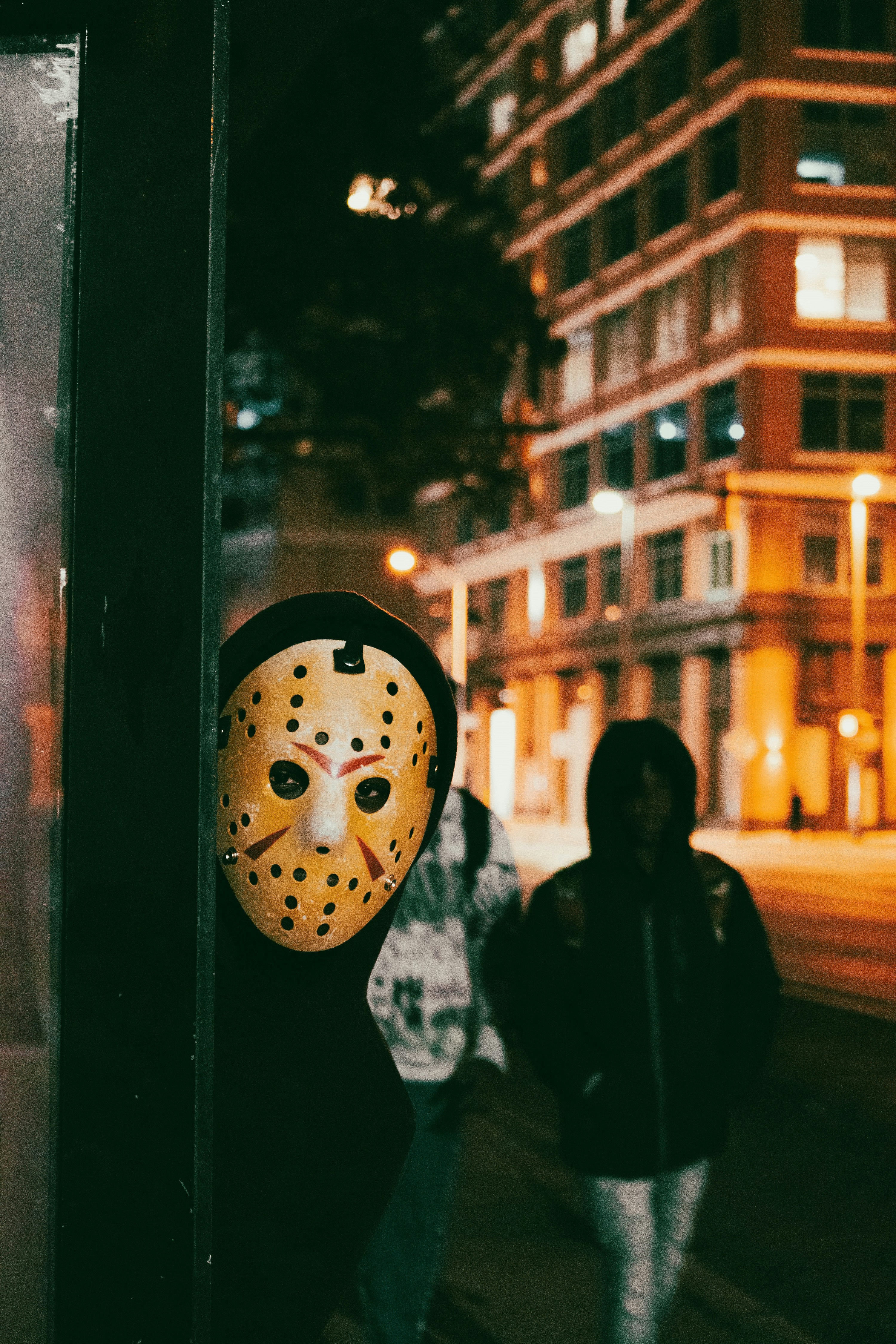 A person standing next to a pole with a mask on it photo – Free ...