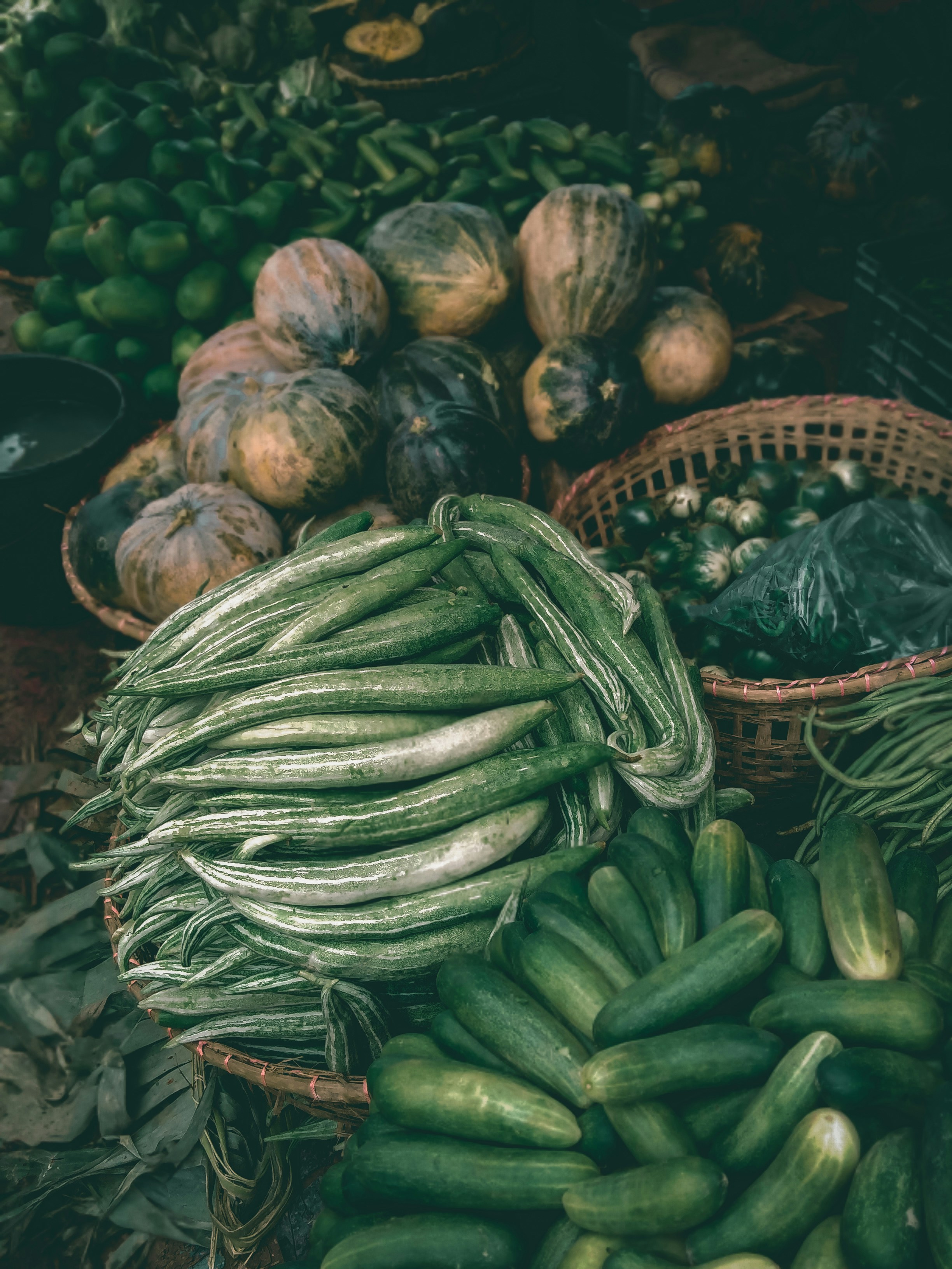A vibrant display of fresh vegetables including cucumbers and gourds in a bustling market setting.