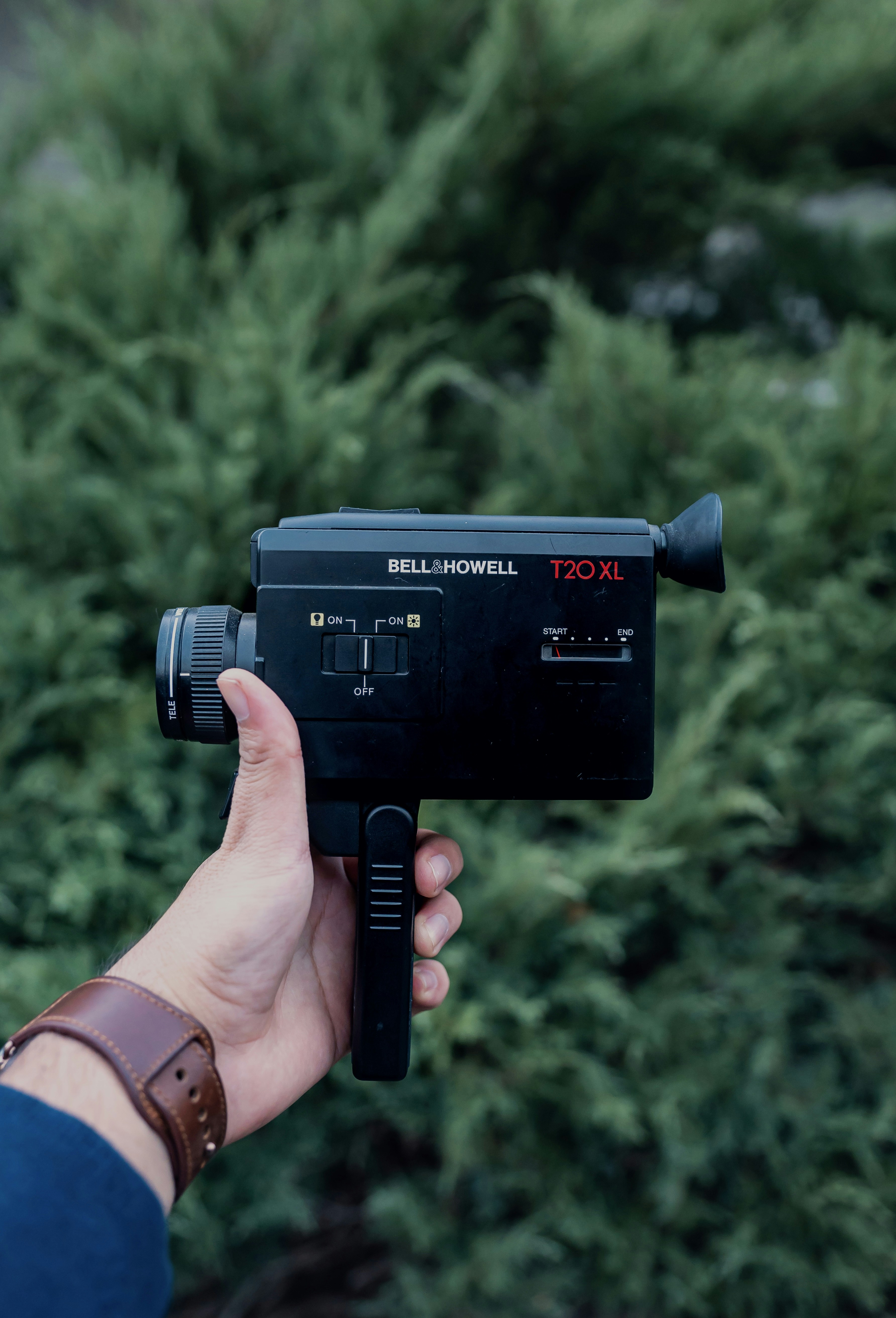 Gripped Relic: Bell & Howell T20 XL Against a Verdant Backdrop