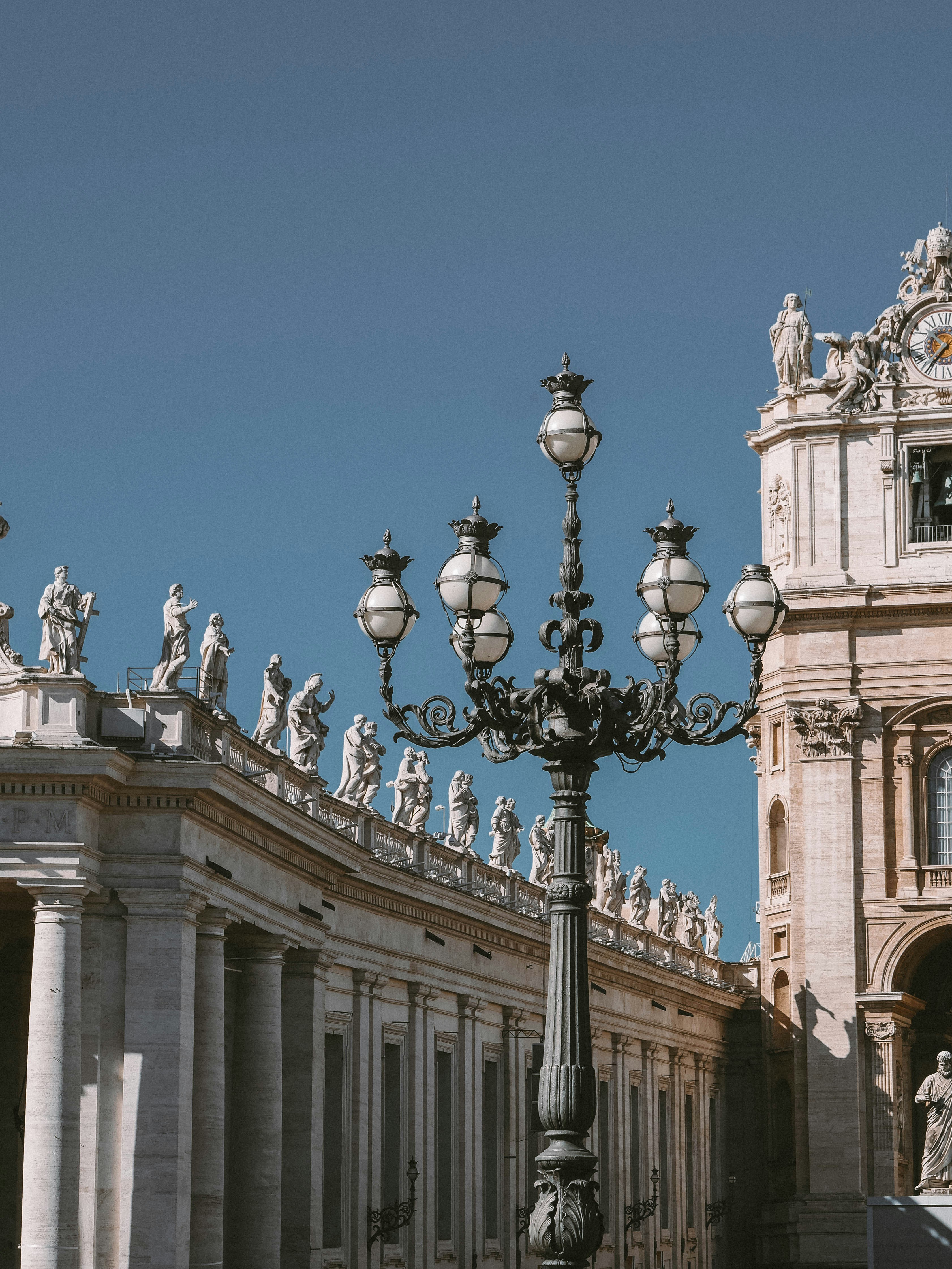 A street light in front of a building with statues on it photo – Free ...
