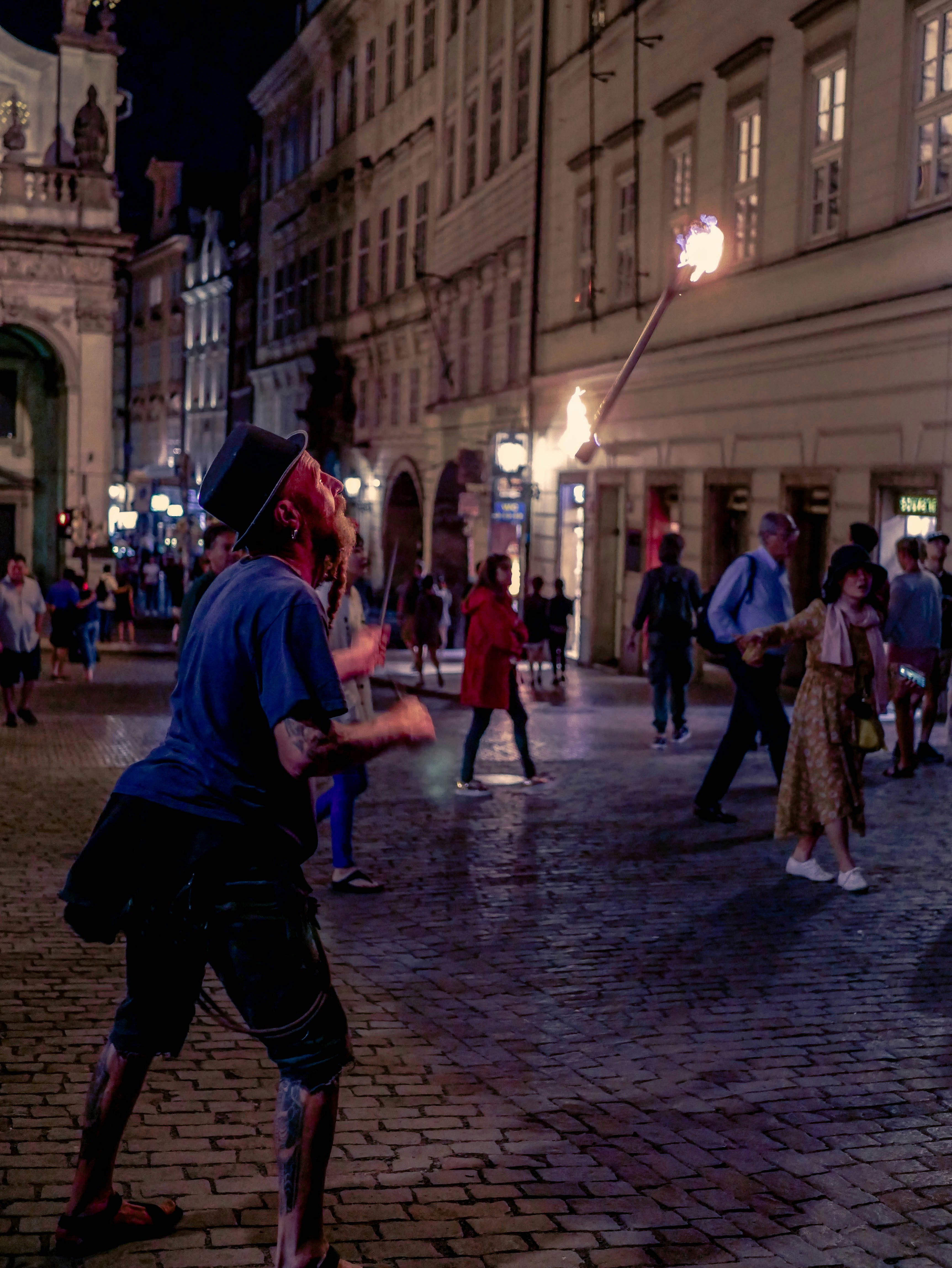 Cobbled Nightfire: A Street Performer Flings Flames Under City Lanterns