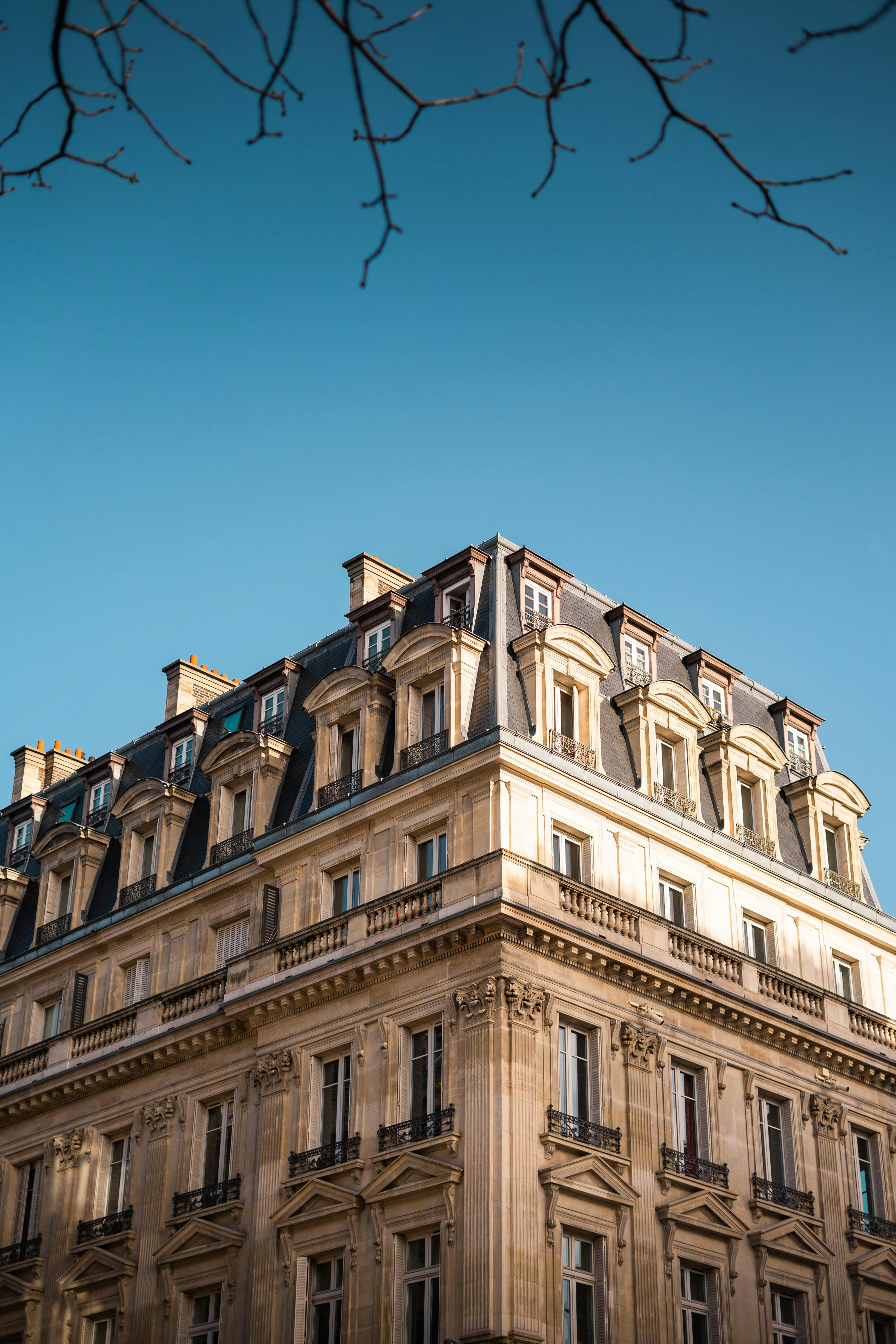 Classic French building facade with intricate details under a bright blue sky.