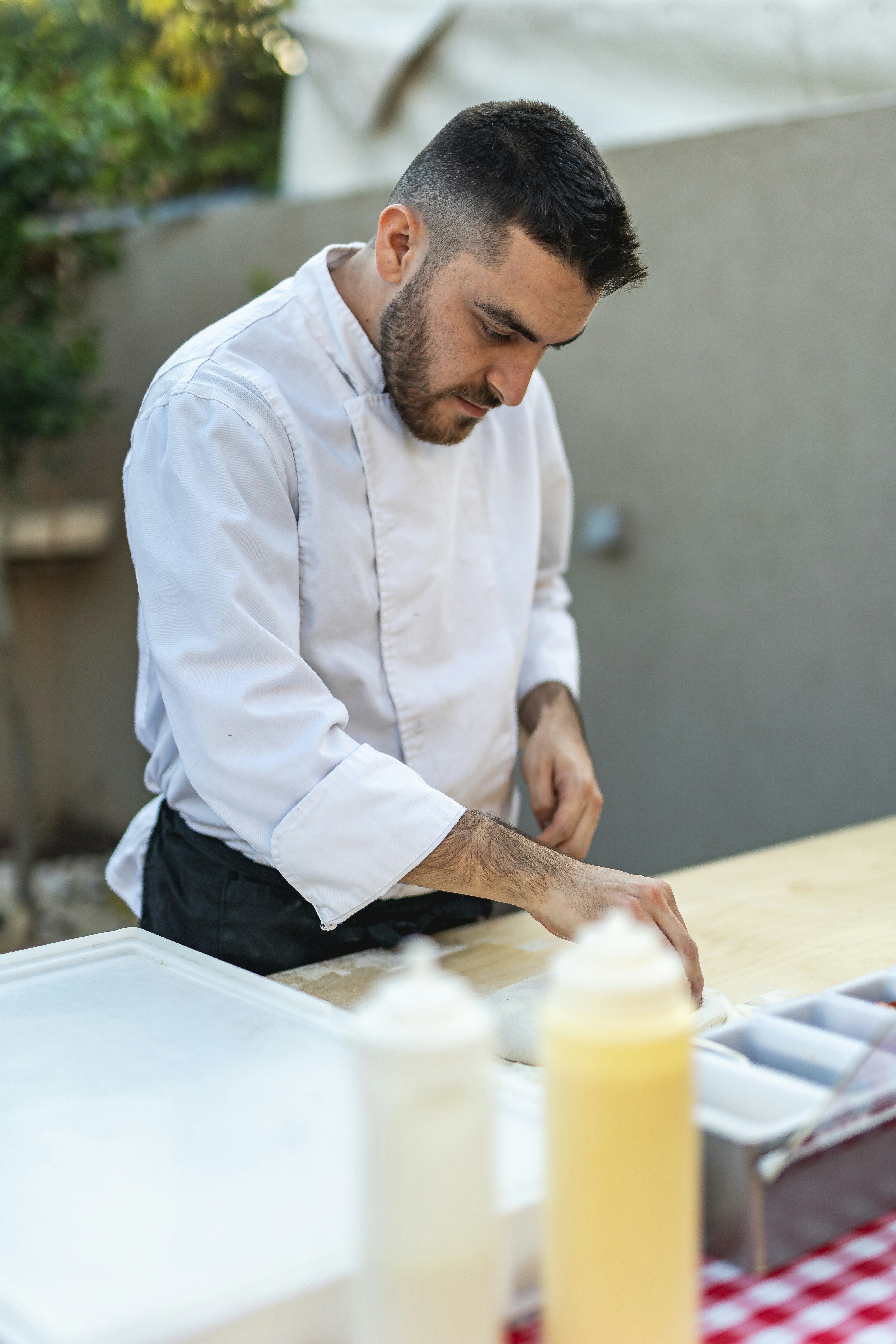 Sunlit Prep: A Chef Delicately Finishes Sauces at an Outdoor Station