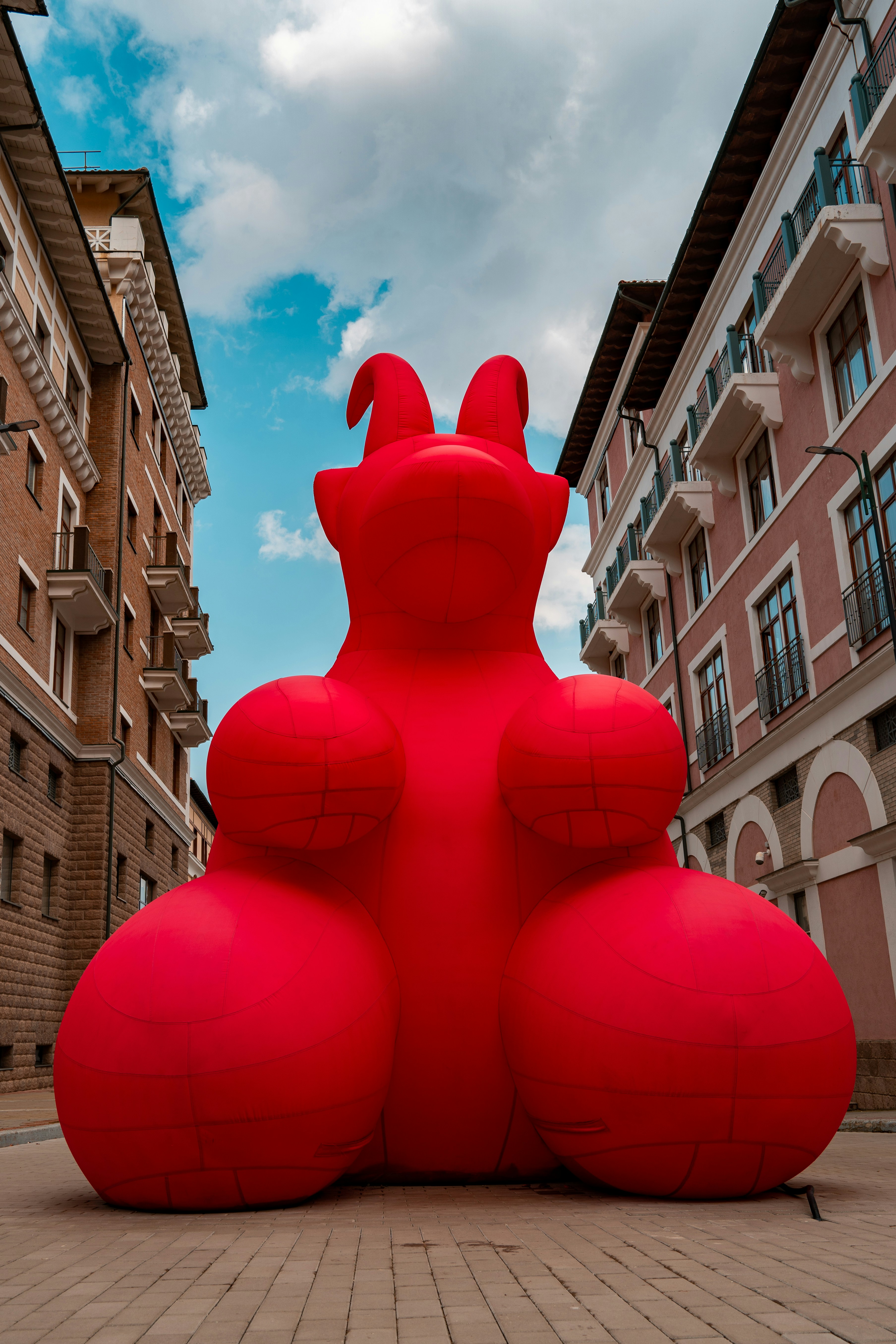Giant Red Figure Anchoring a Quiet Street