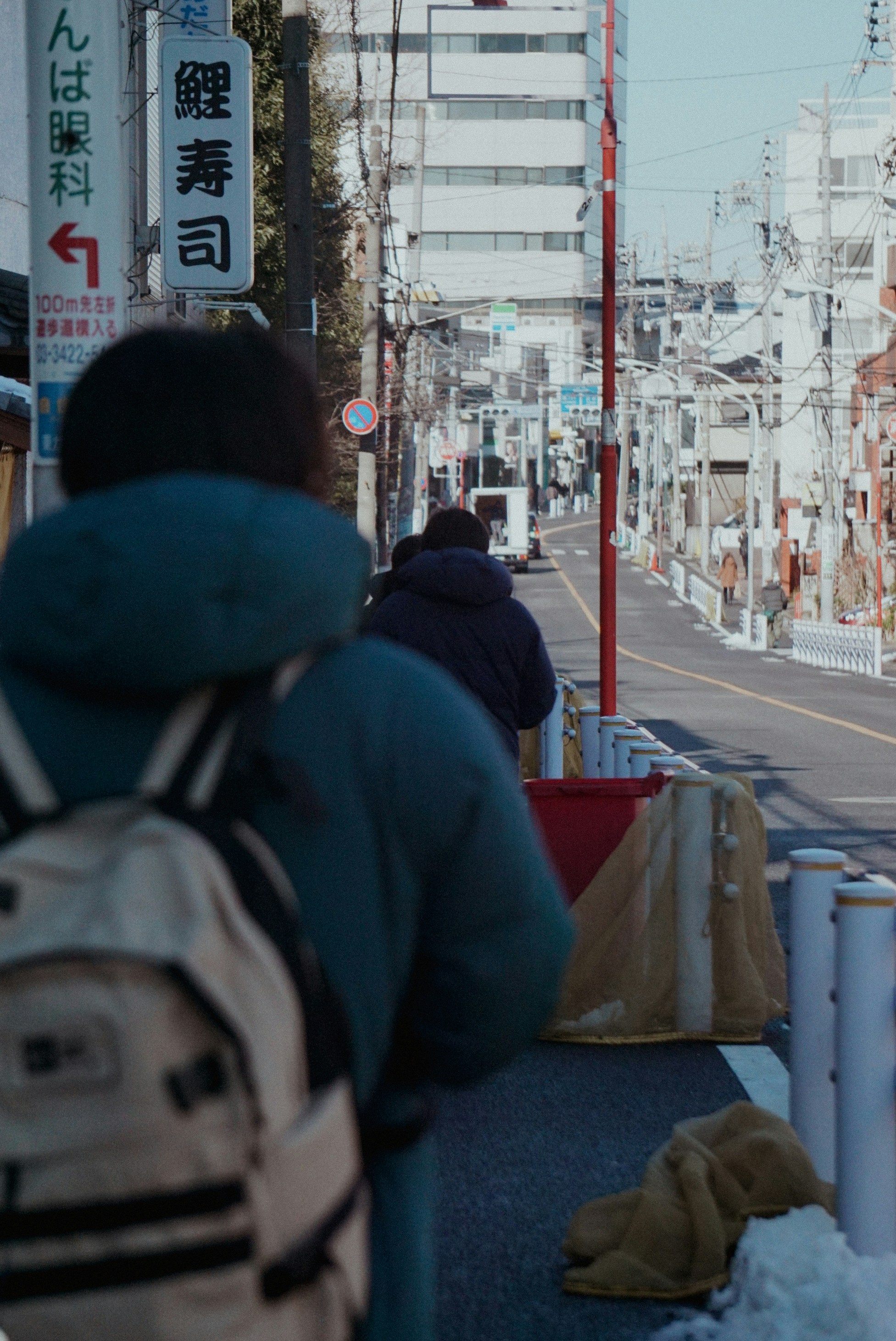 Teal-clad commuter anchors a quiet Tokyo street
