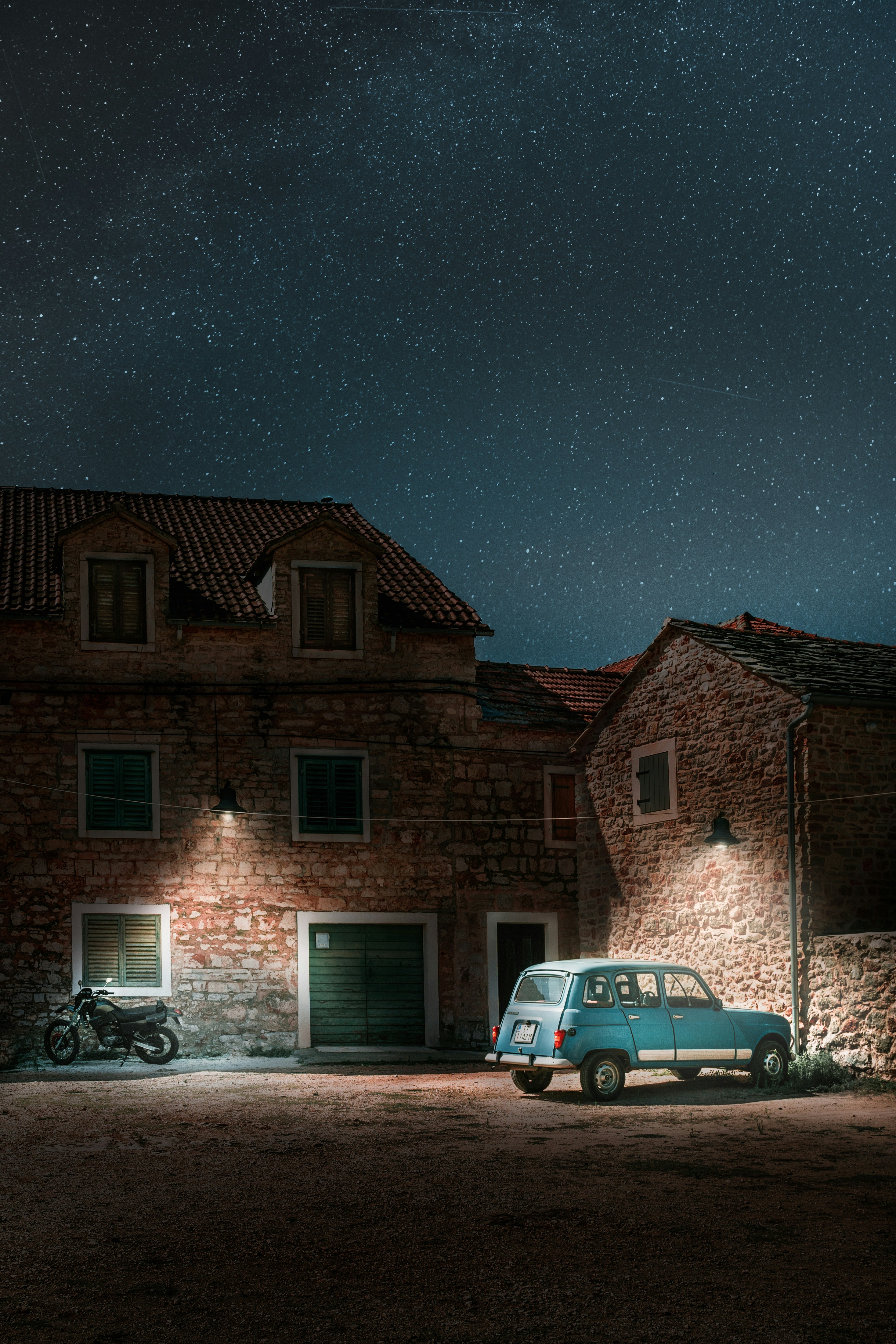 Blue Classic Car in a Moonlit Stone Courtyard Beneath a Sea of Stars