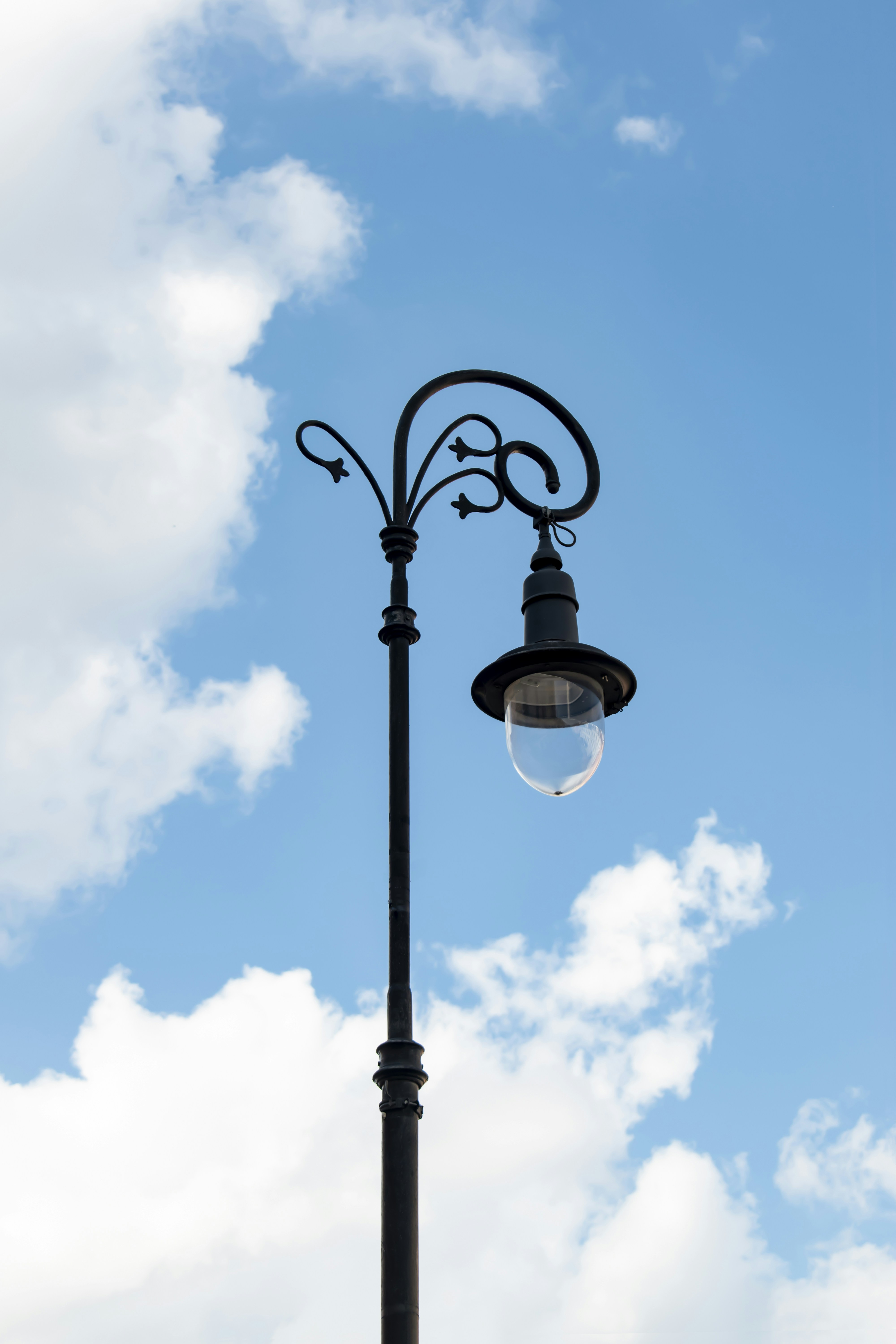Retro black street lamp on sunny day | a street light with a sky background