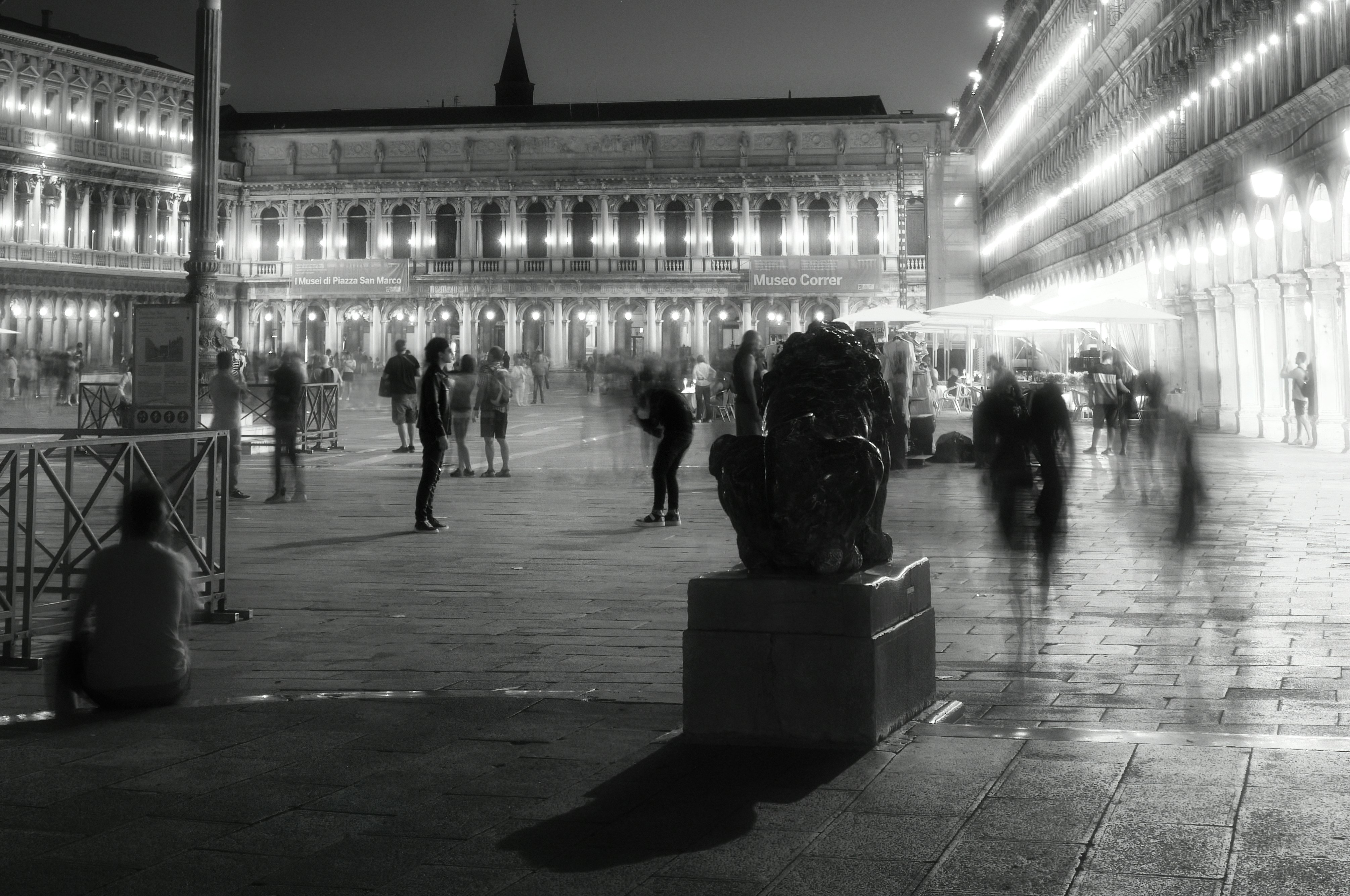 The Night Sentinel: Lion Sculpture Amidst a Blur of Footfall