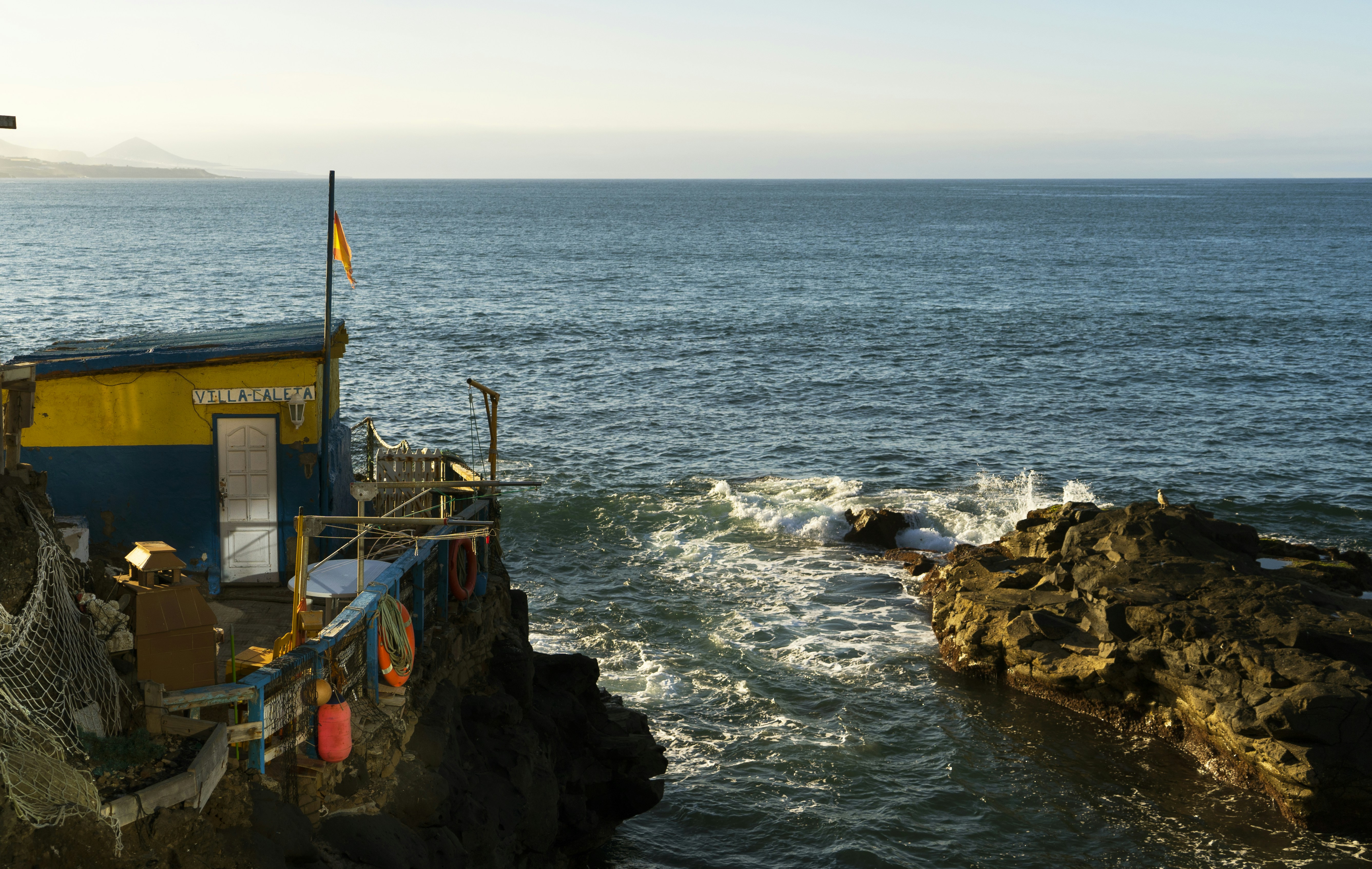 Bright Shack Clinging to Coastal Rocks Under a Quiet Horizon