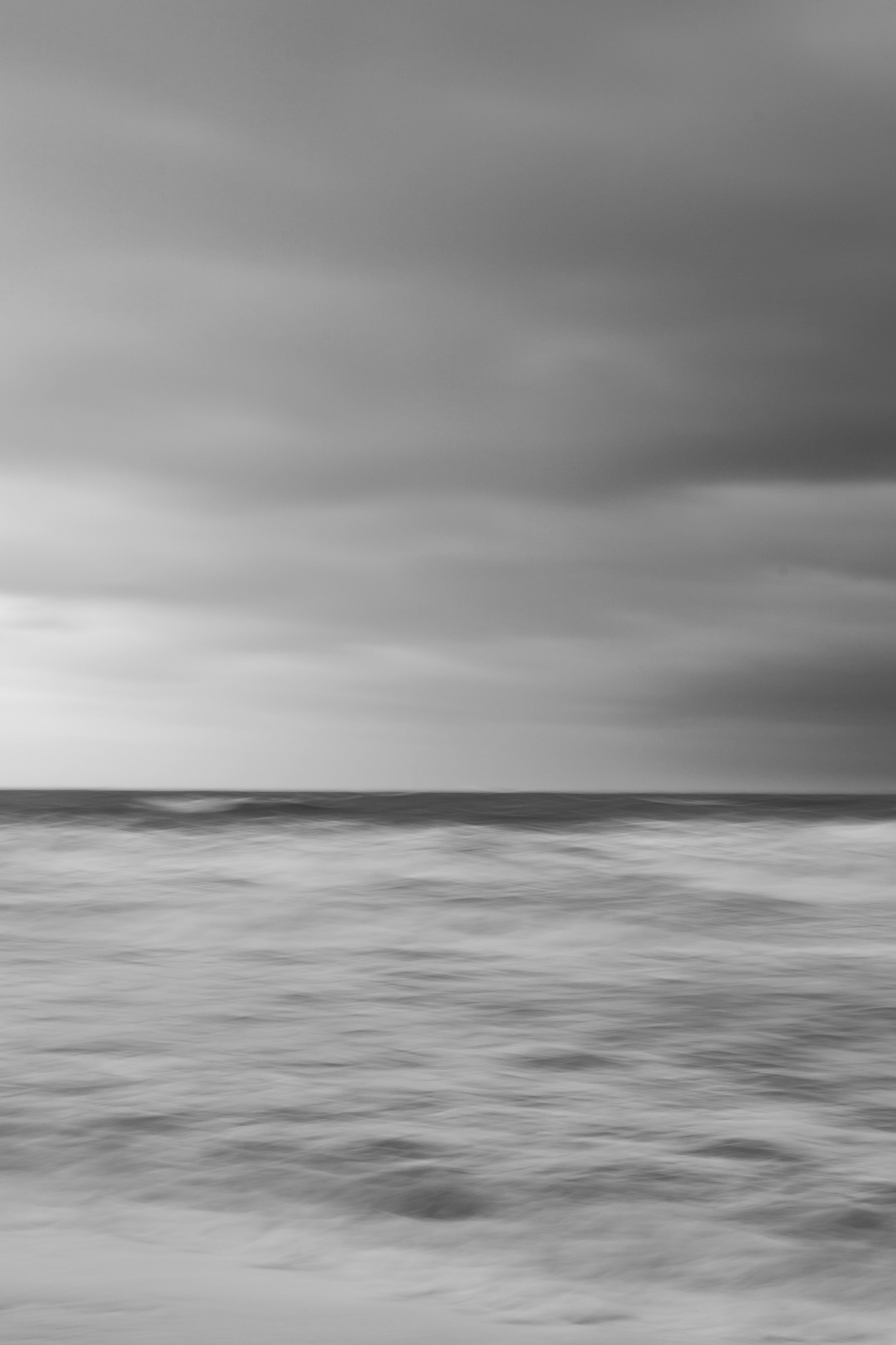 Long exposure of ocean waves creating a smooth, misty effect under a dramatic, cloudy sky.