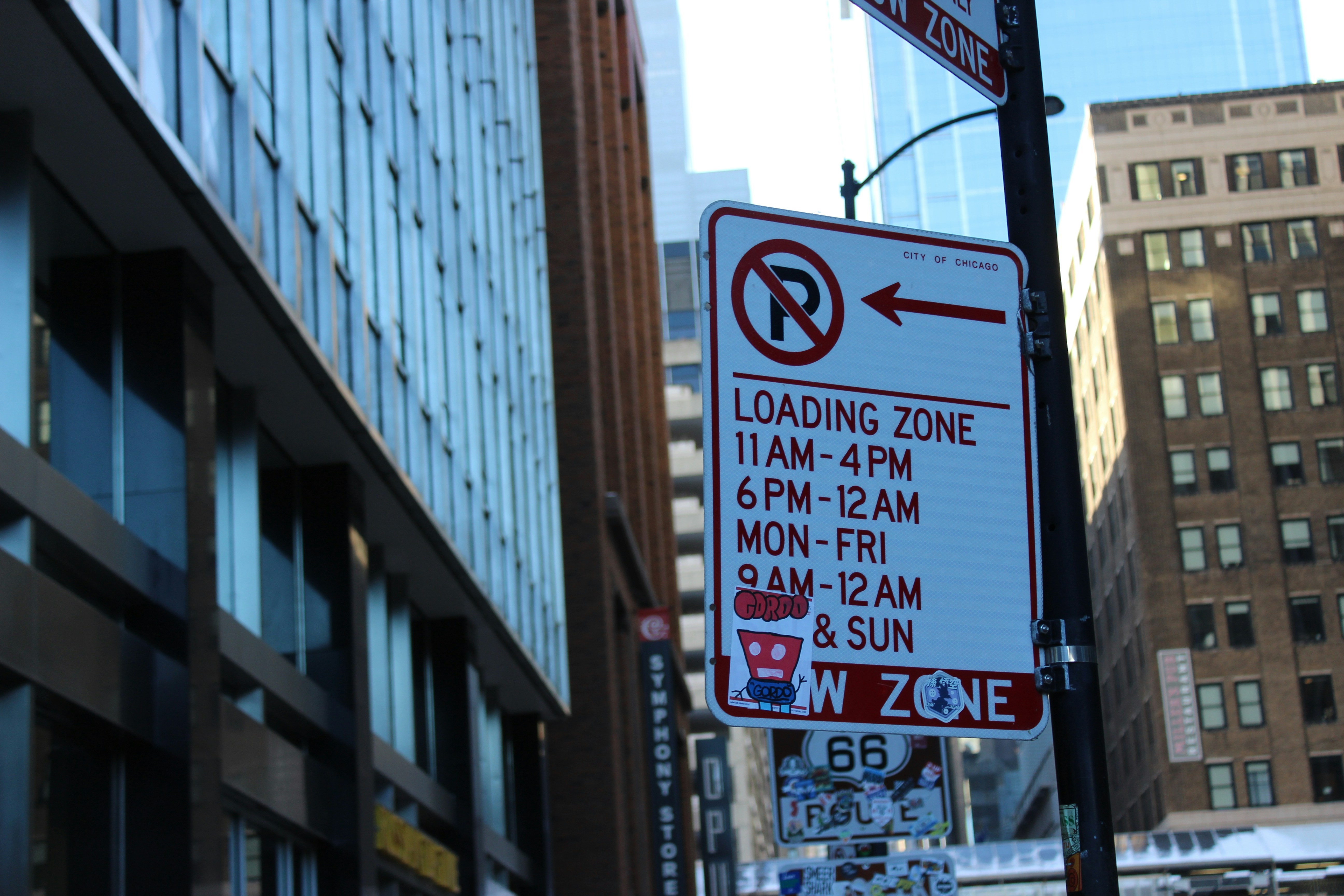 No parking sign detailing loading zone hours in a bustling city street.