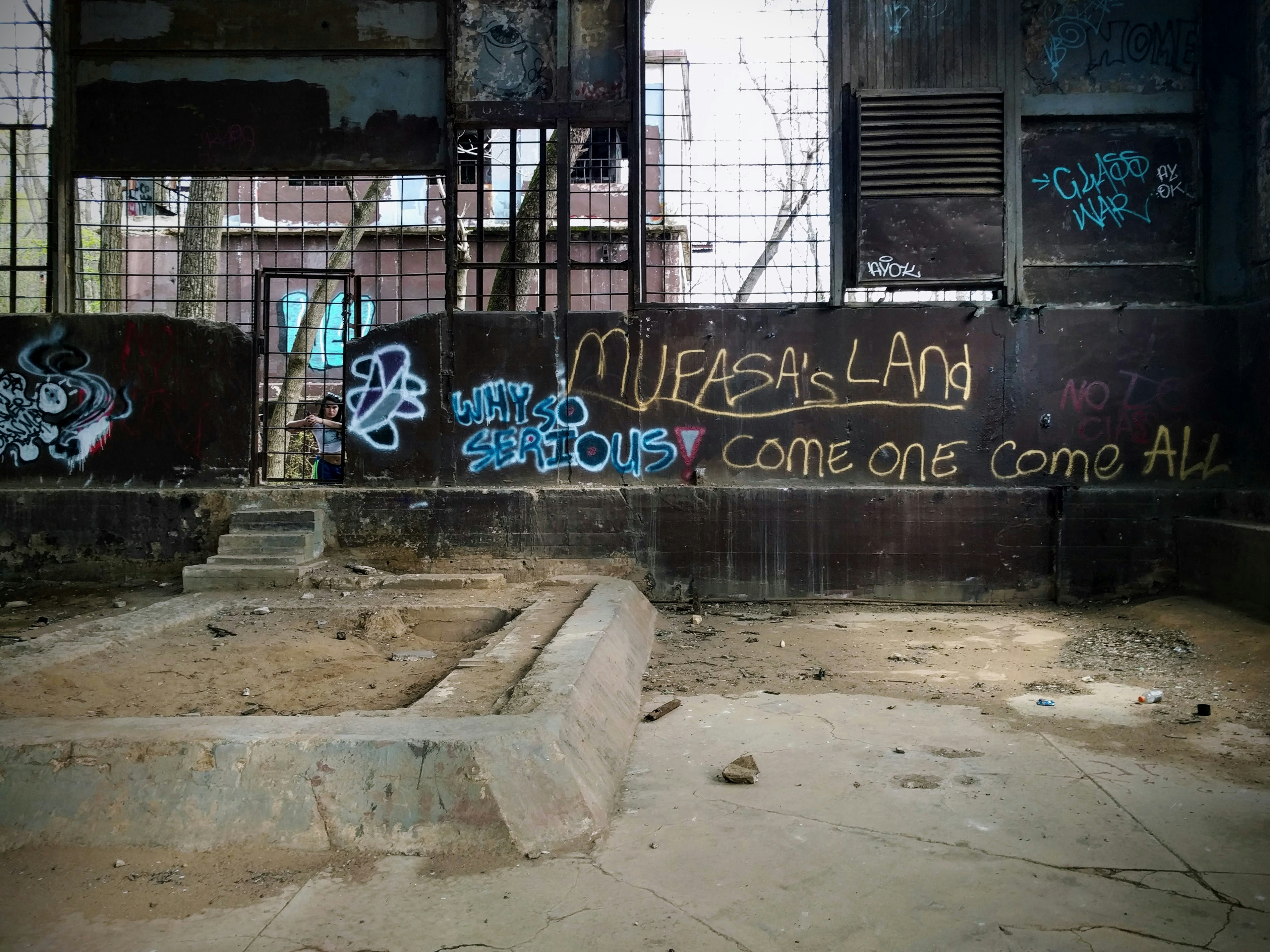 Graffiti-covered wall in an abandoned urban space with a concrete platform and rubble.