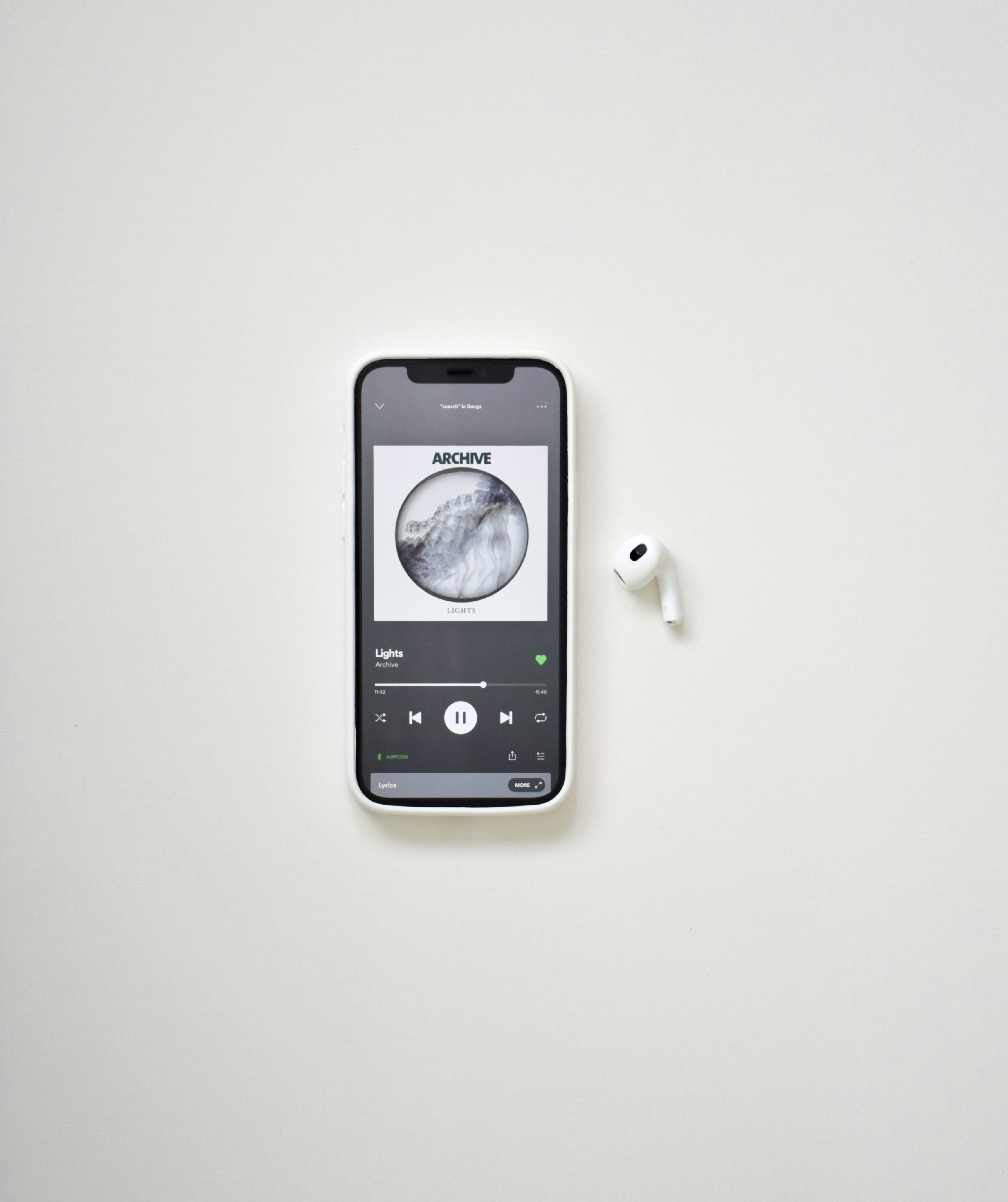 Smartphone displaying a music streaming app with album artwork, accompanied by a single wireless earbud on a clean, neutral background.