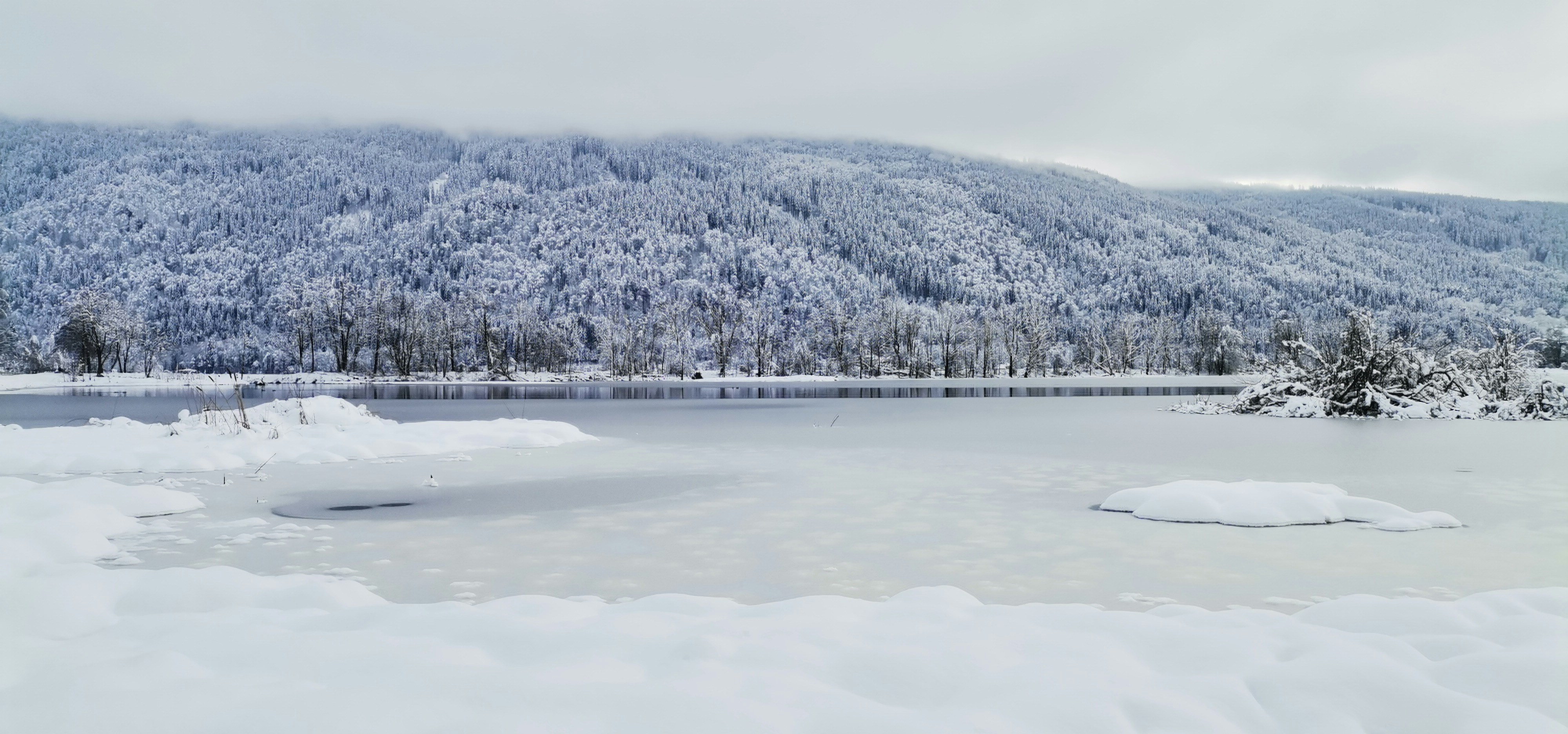 A frozen lake surrounded by snow covered mountains photo – Free Austria ...
