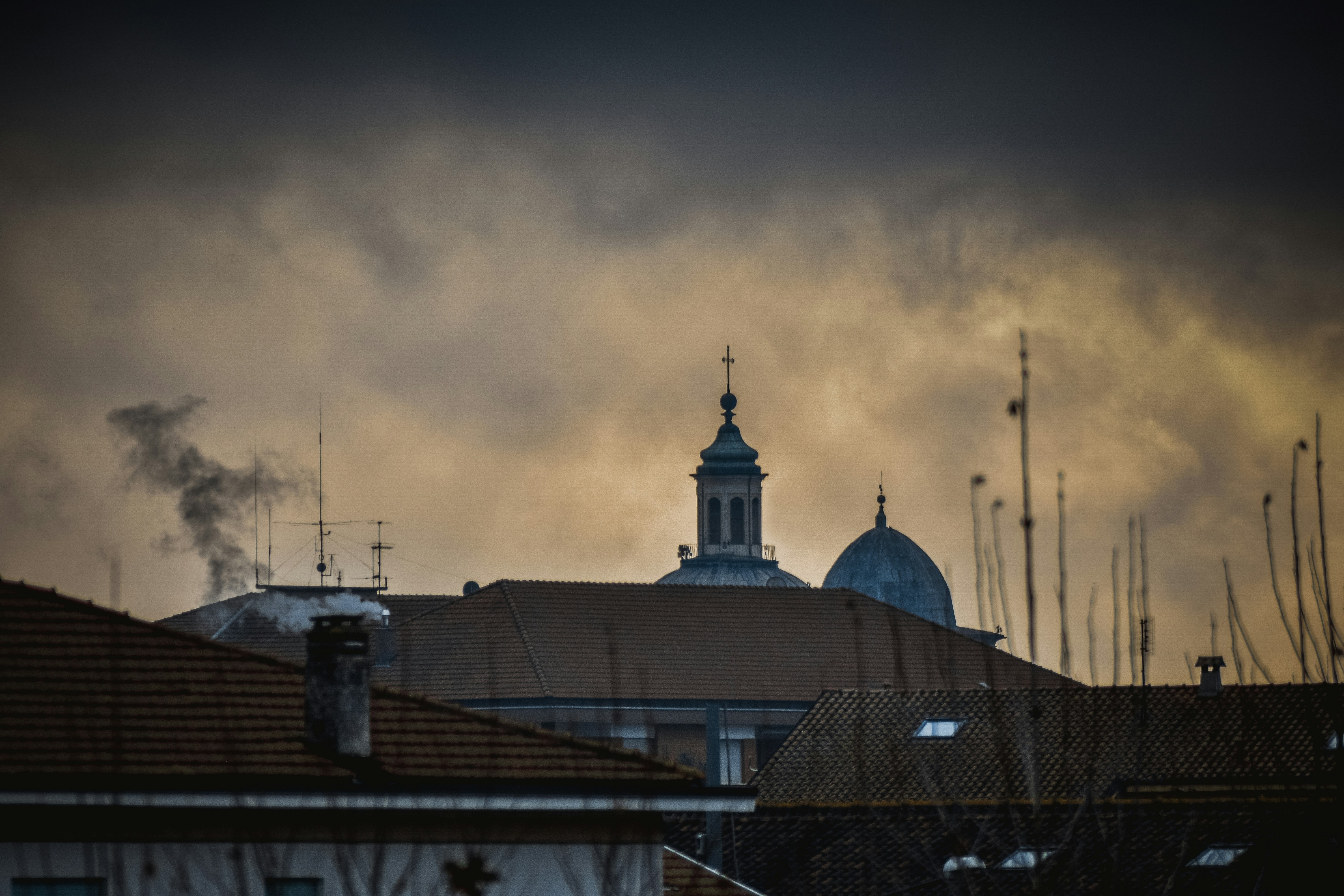 Clock tower and dome silhouetted against a dramatic, cloudy sky.