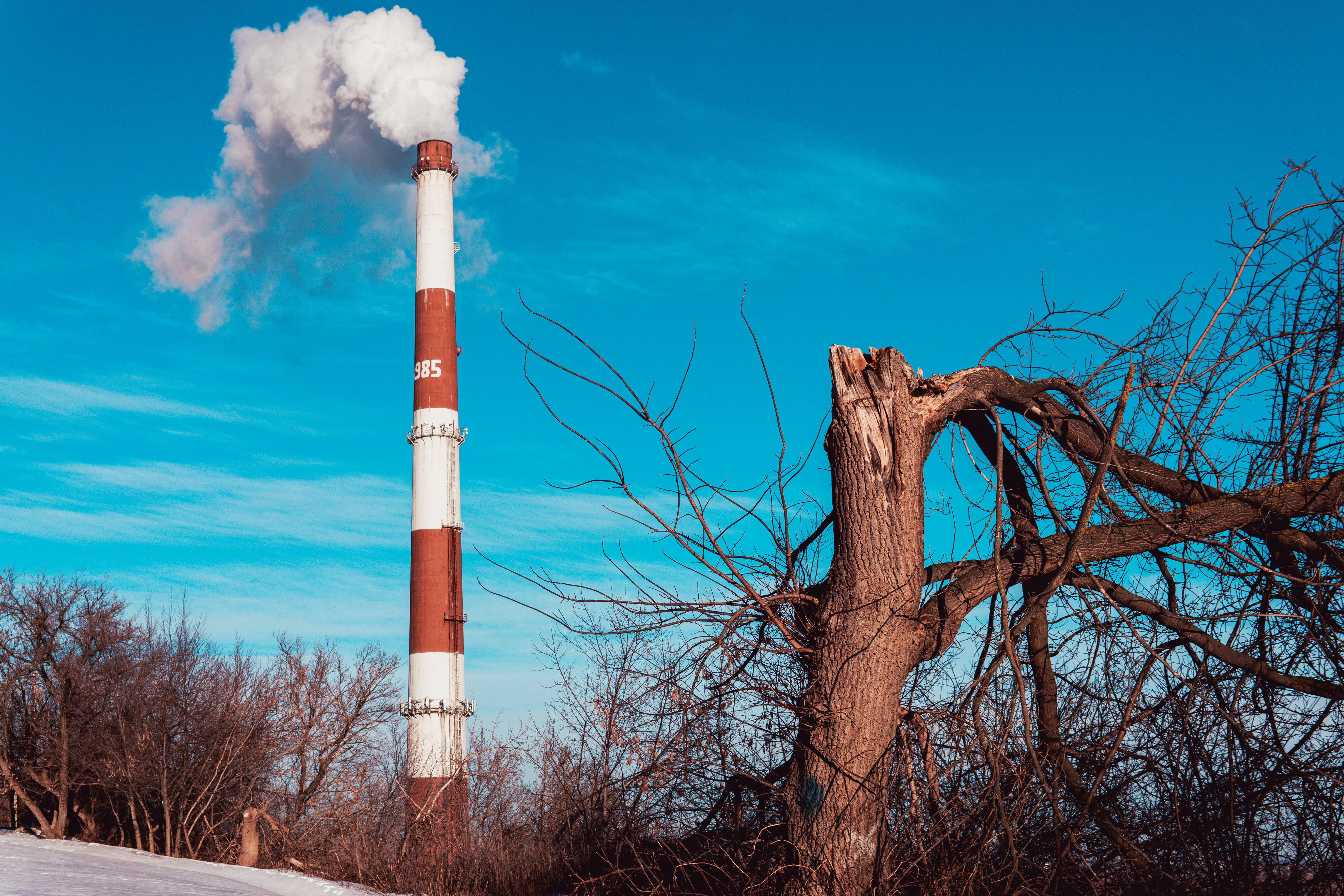 Striped smokestack piercing the cobalt winter sky