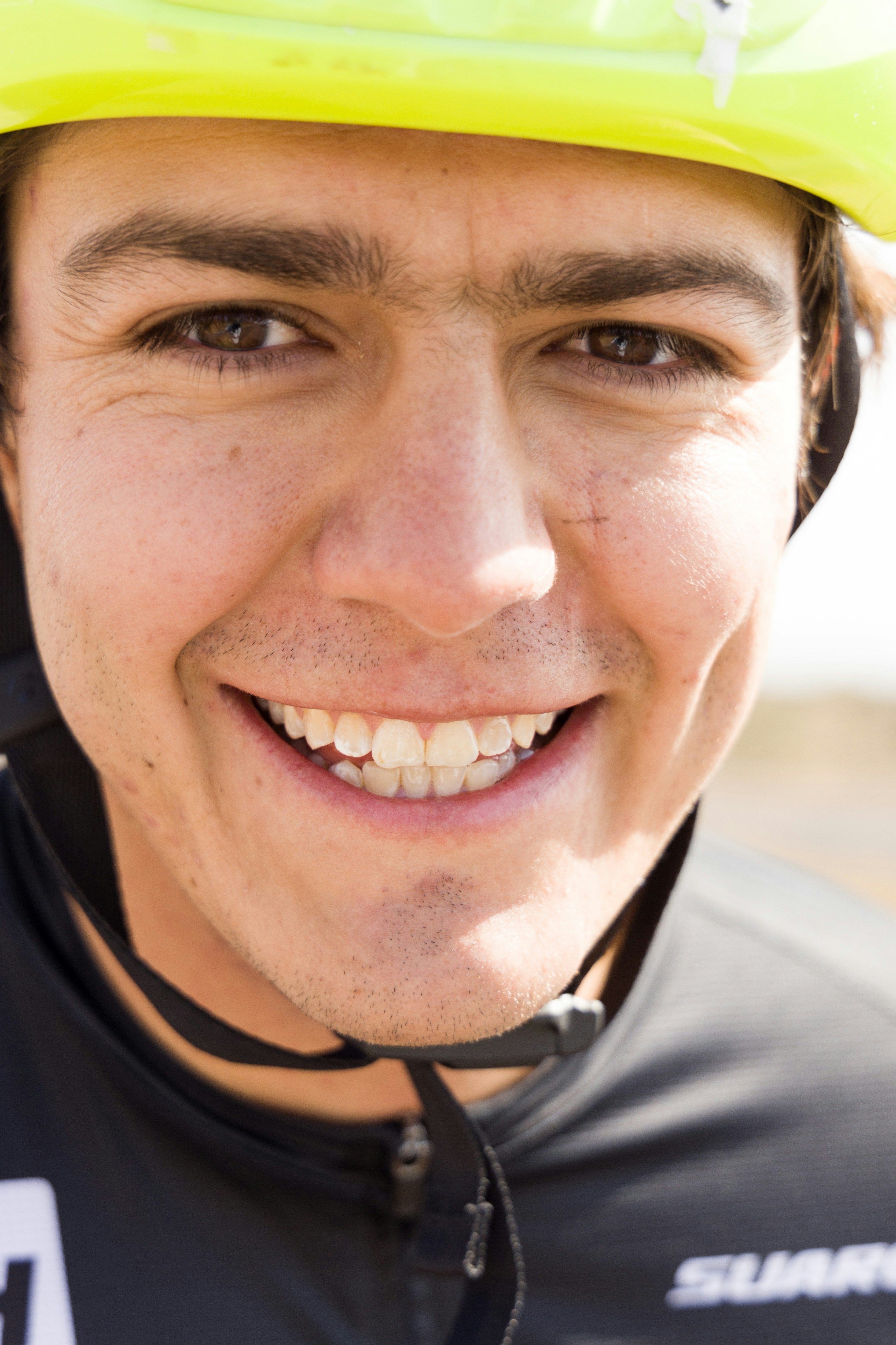 Close-up of a smiling cyclist in a yellow helmet