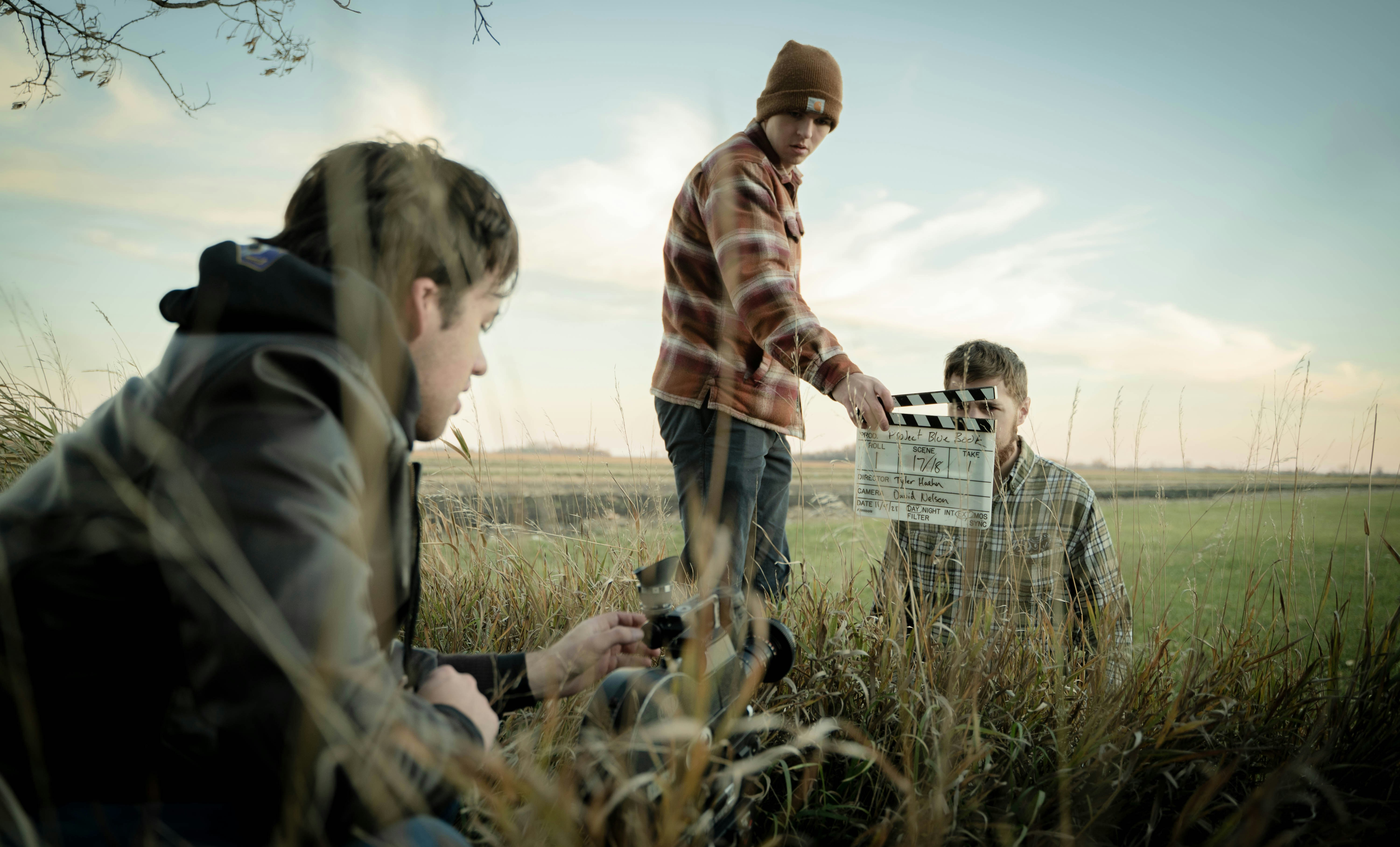 a group of young men sitting on top of a grass covered field