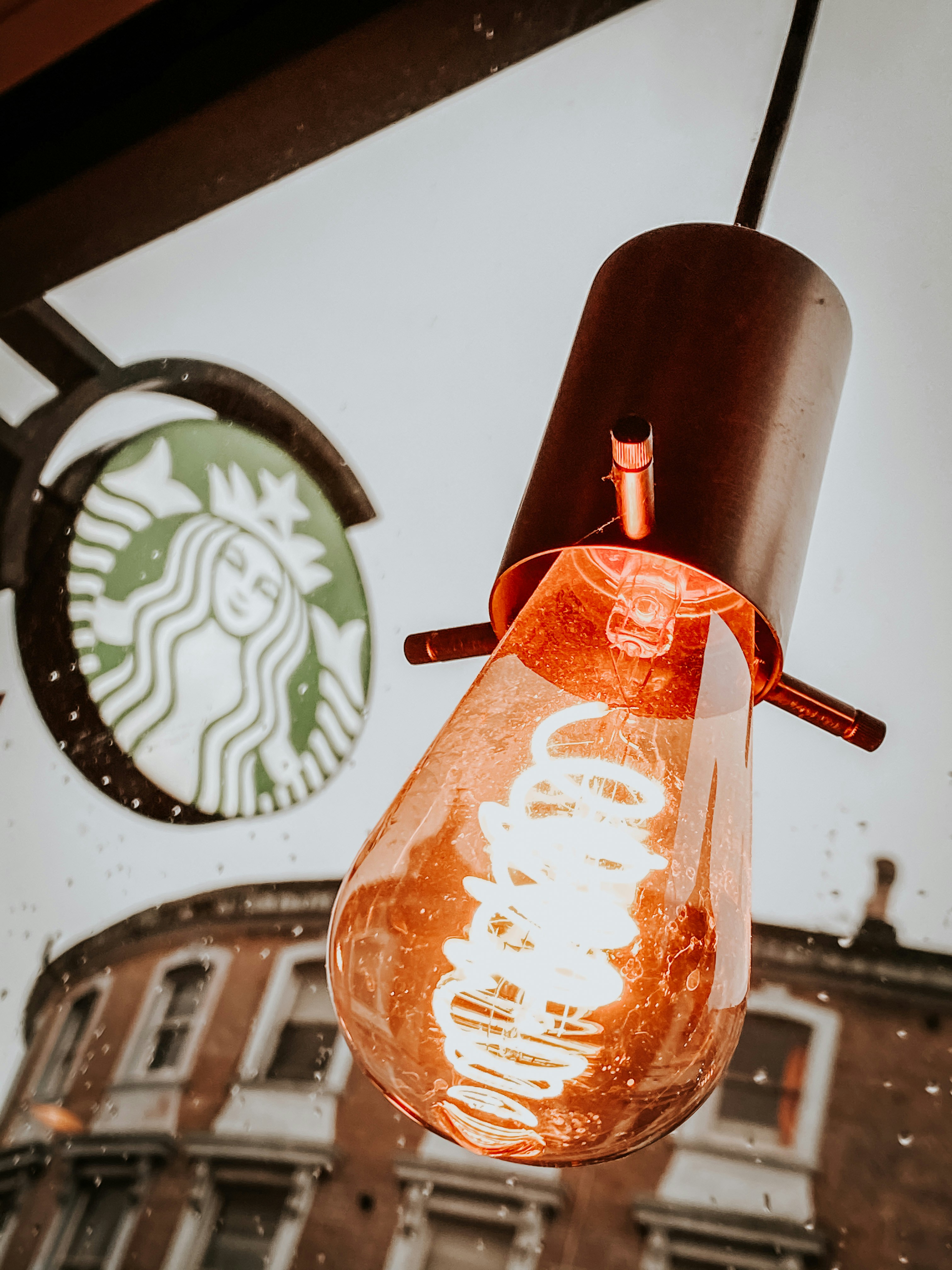 A starbucks sign hanging from the side of a building photo – Free Drink ...