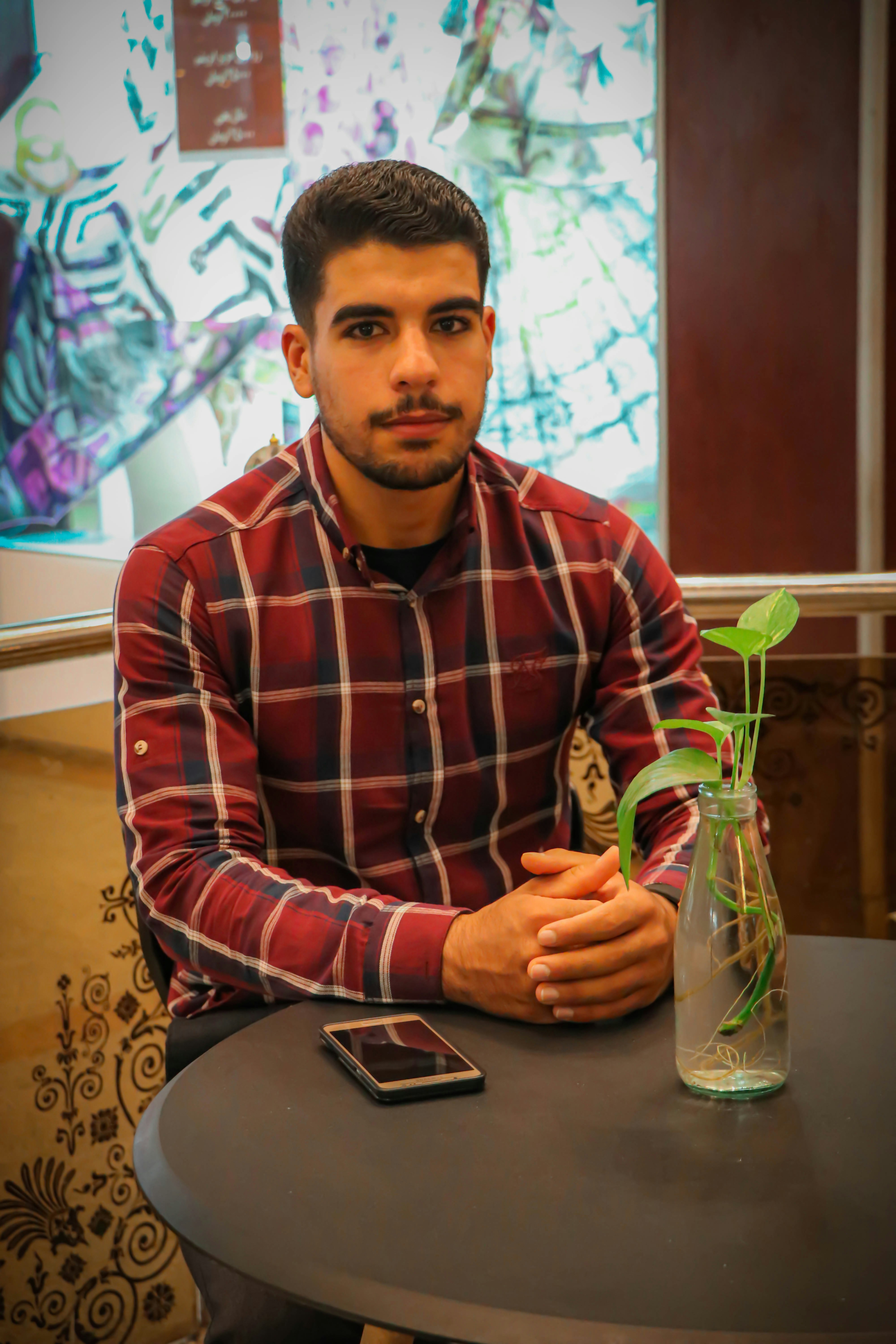 Un homme assis à une table avec un vase de fleurs photo – Photo La ...