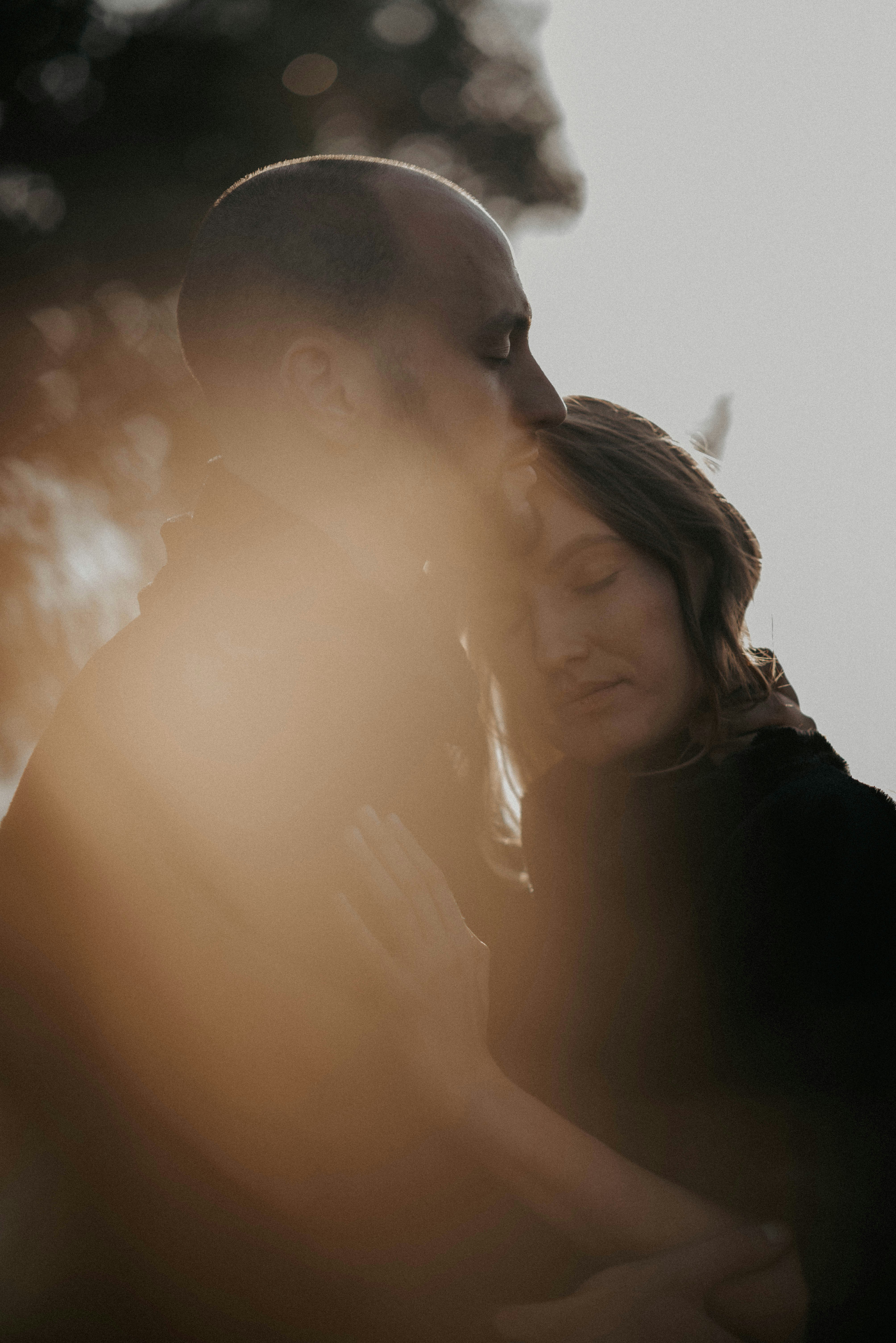 Golden Backlight Embrace: Tender closeness in a hazy, sun-kissed frame