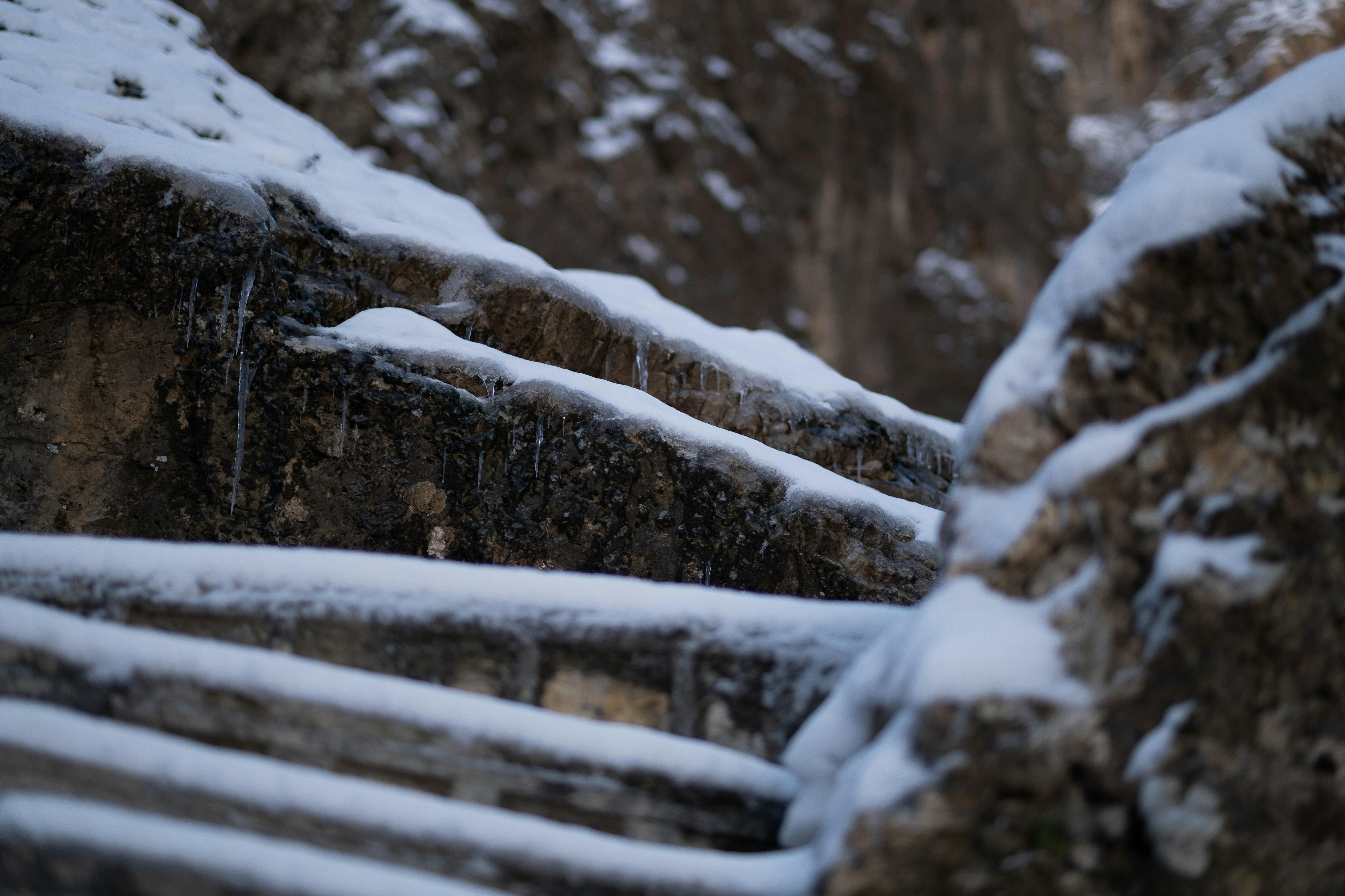 A stone wall covered in snow next to a cliff photo – Free Snow Image on ...