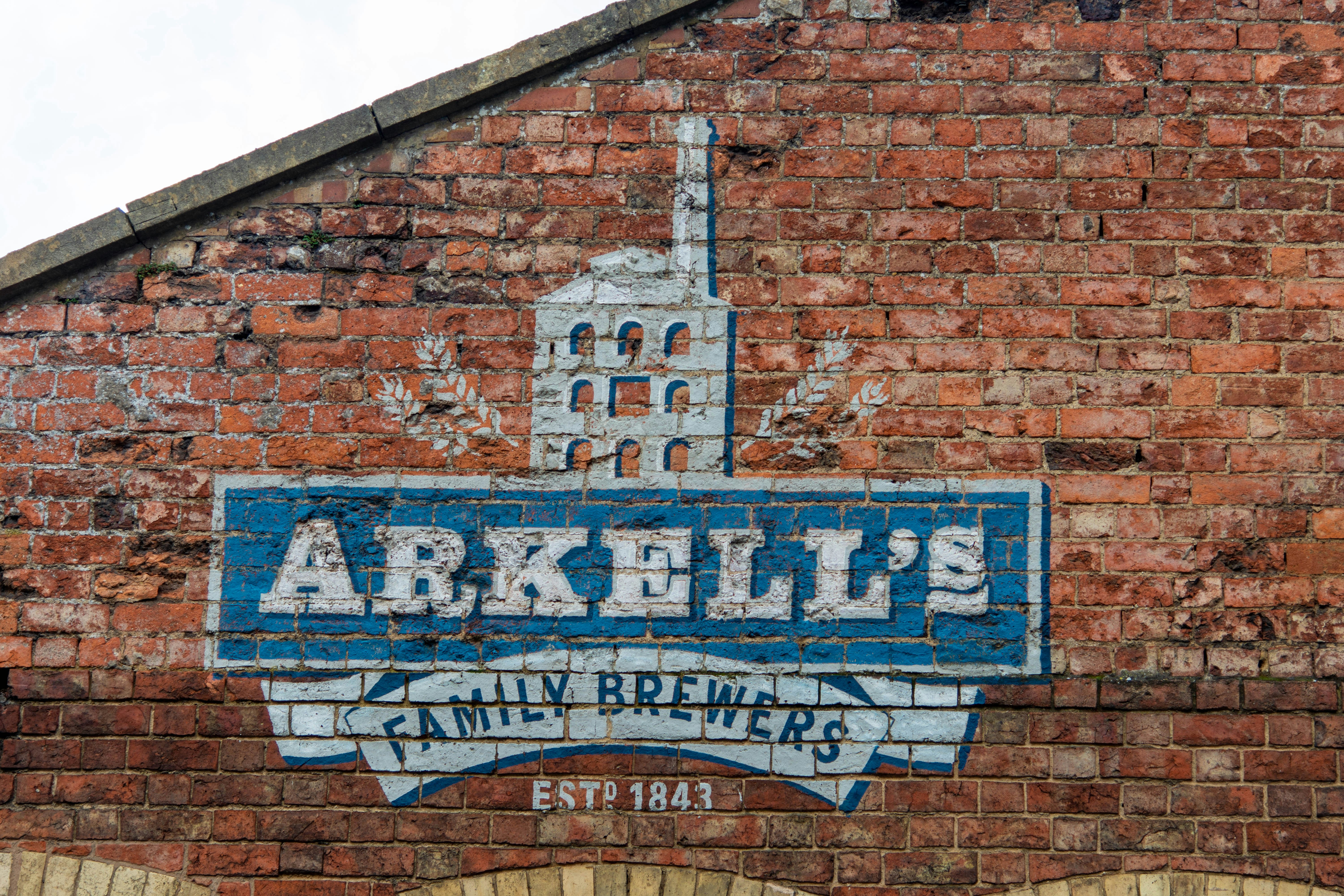 Blue Brickwork Emblem: Arkell's Family Breweries Painted on a Sunlit Wall