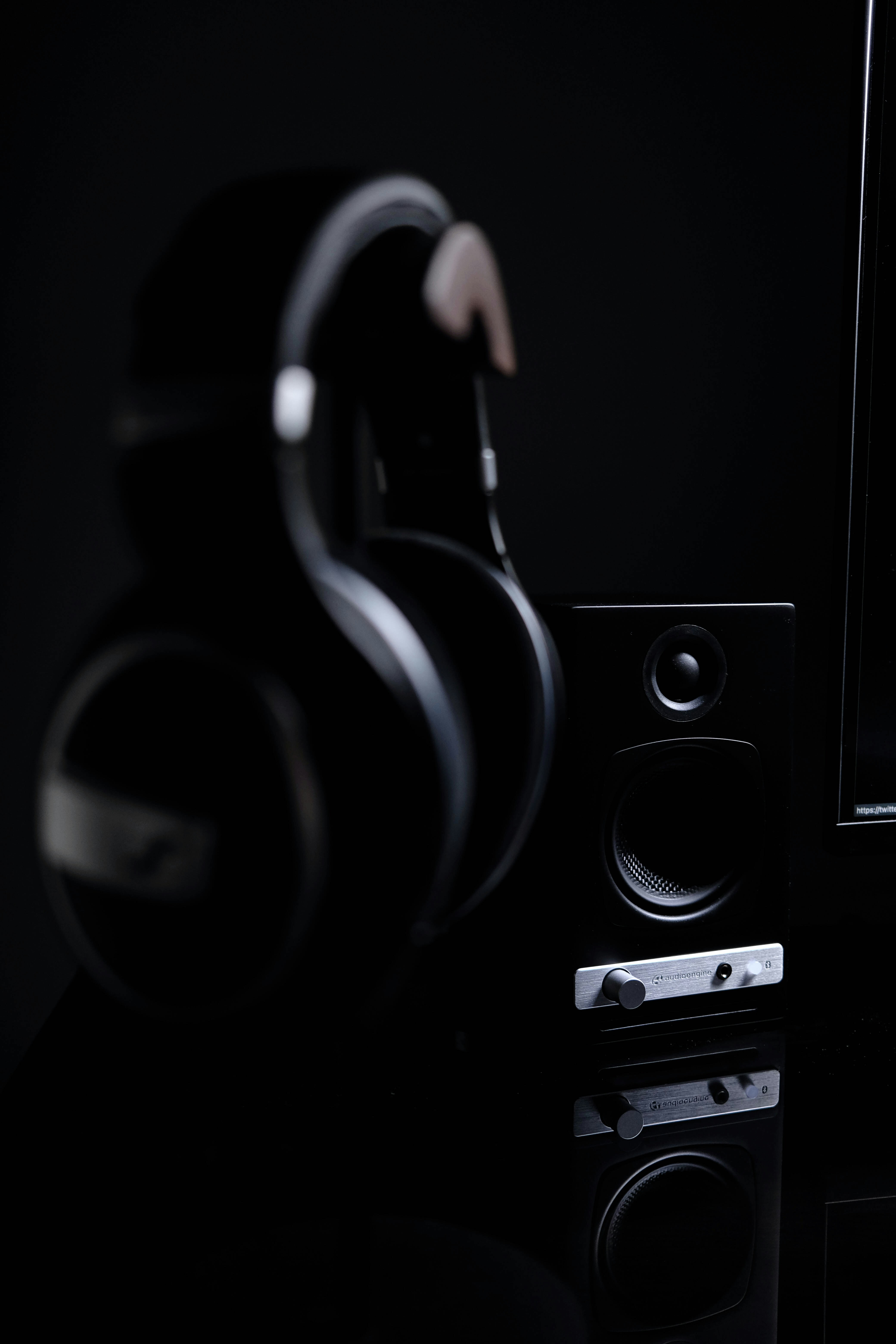 Sleek black headphones beside a compact speaker on a reflective surface, highlighting a modern audio experience.