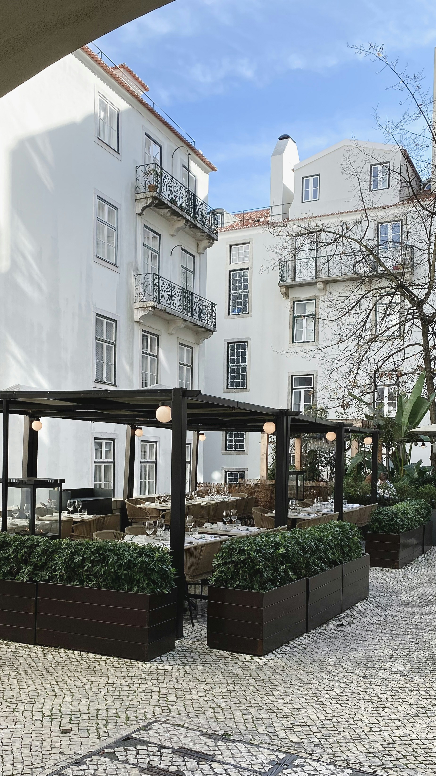 Sunlit Courtyard Bistro Framed by Pale White Facades