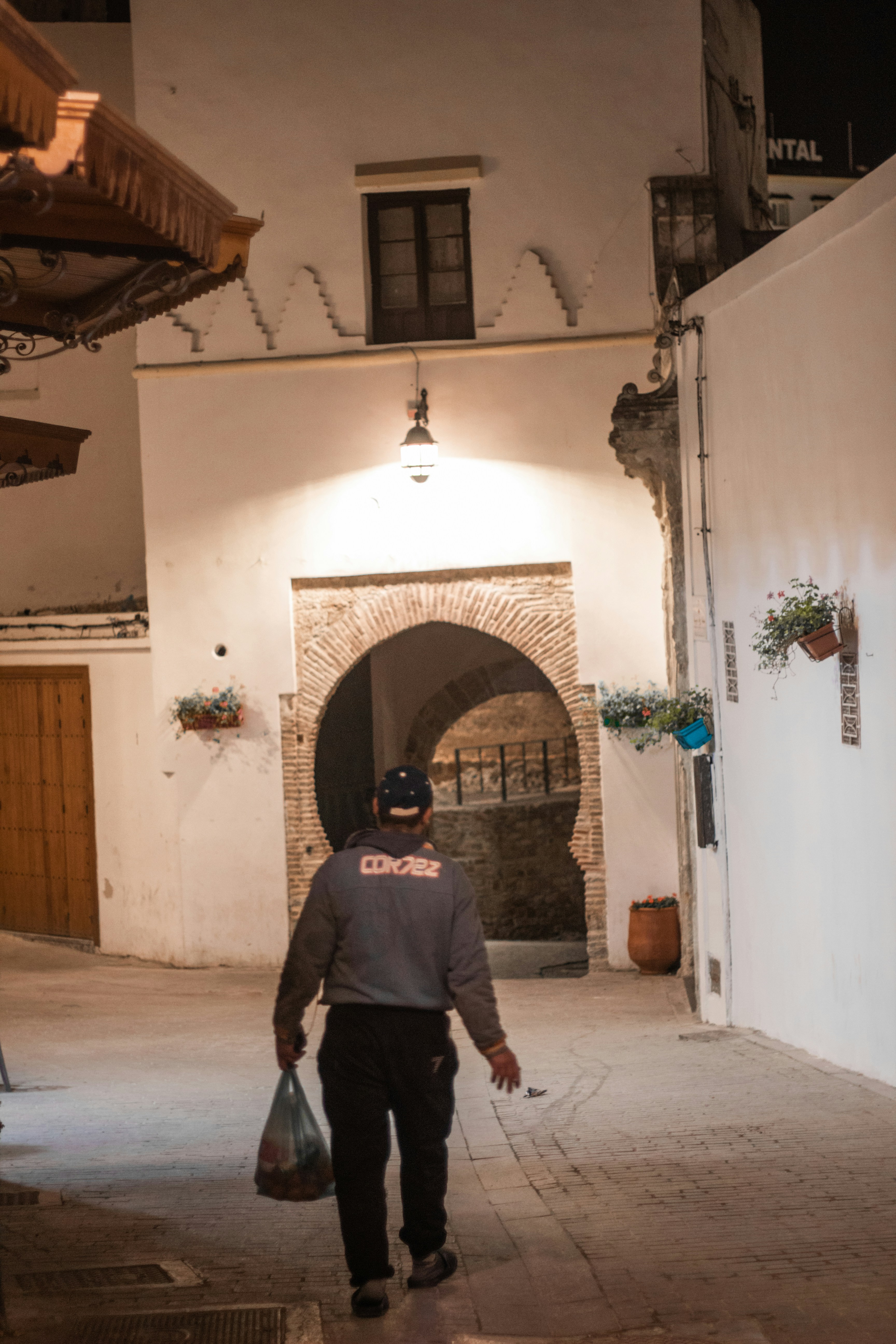 Traveler under the Arch: Night Walk through a Quiet Plaza