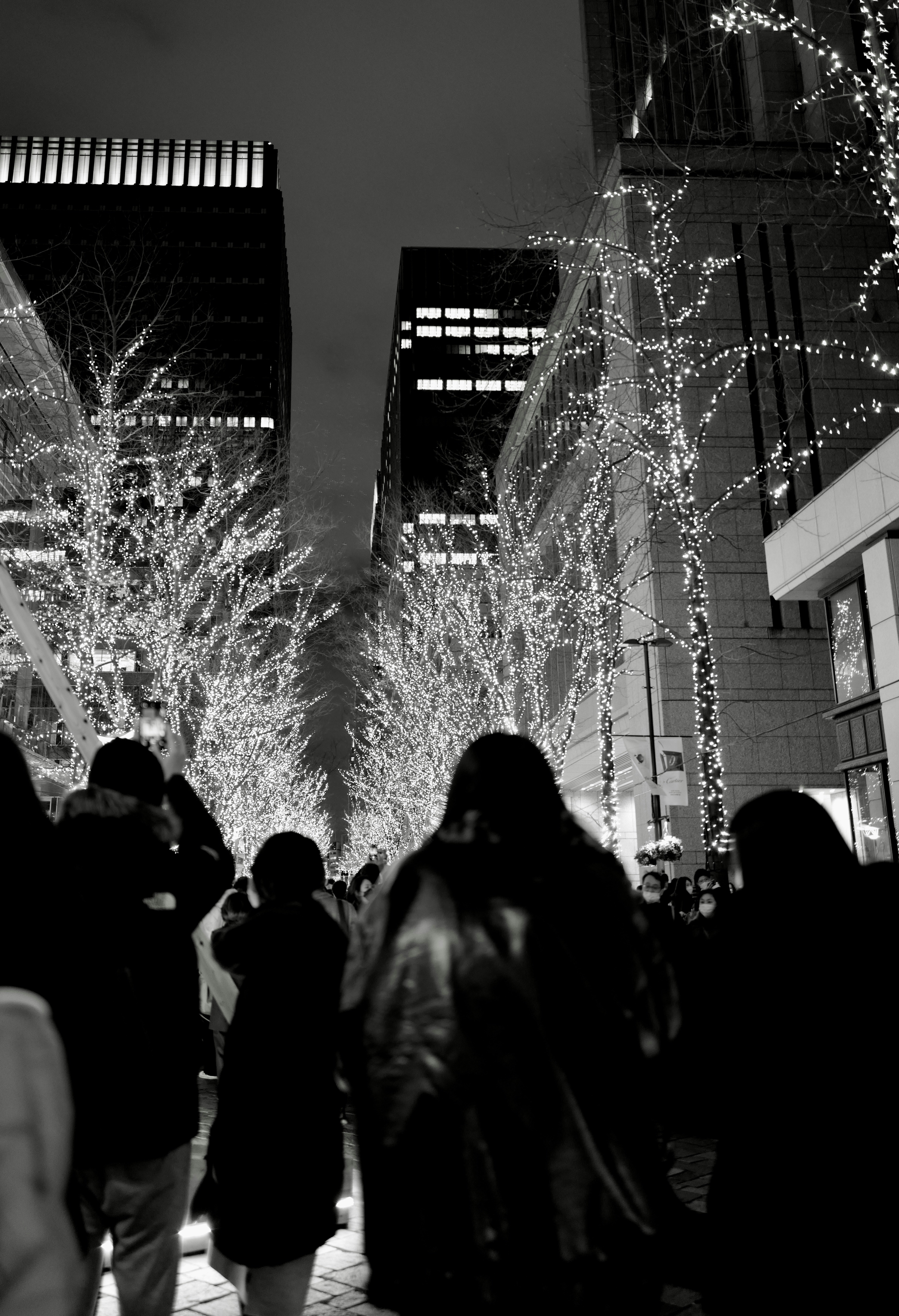 a group of people walking down a street next to tall buildings
