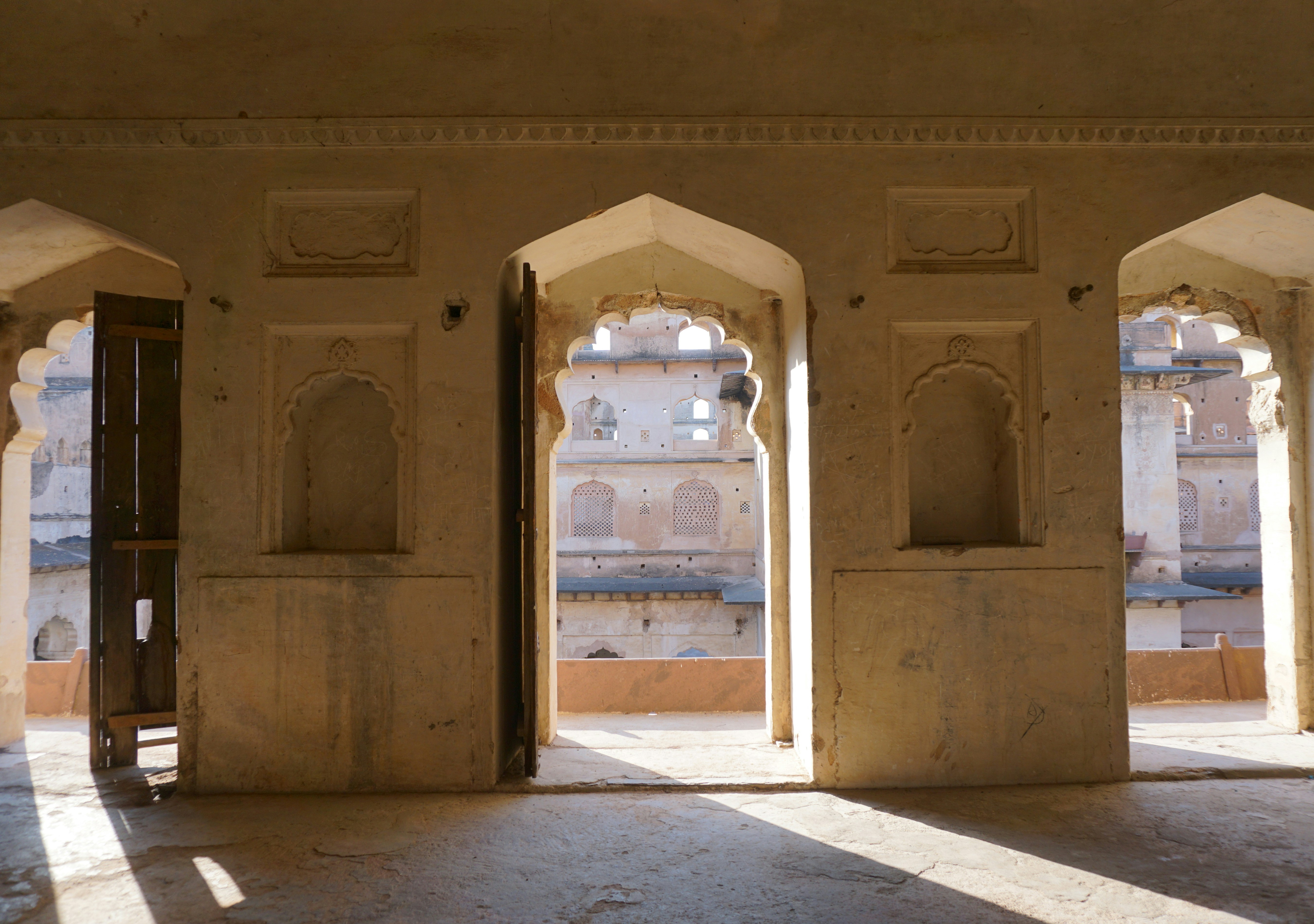 A room with arches and a bench in the middle of it photo – Free Orchha ...