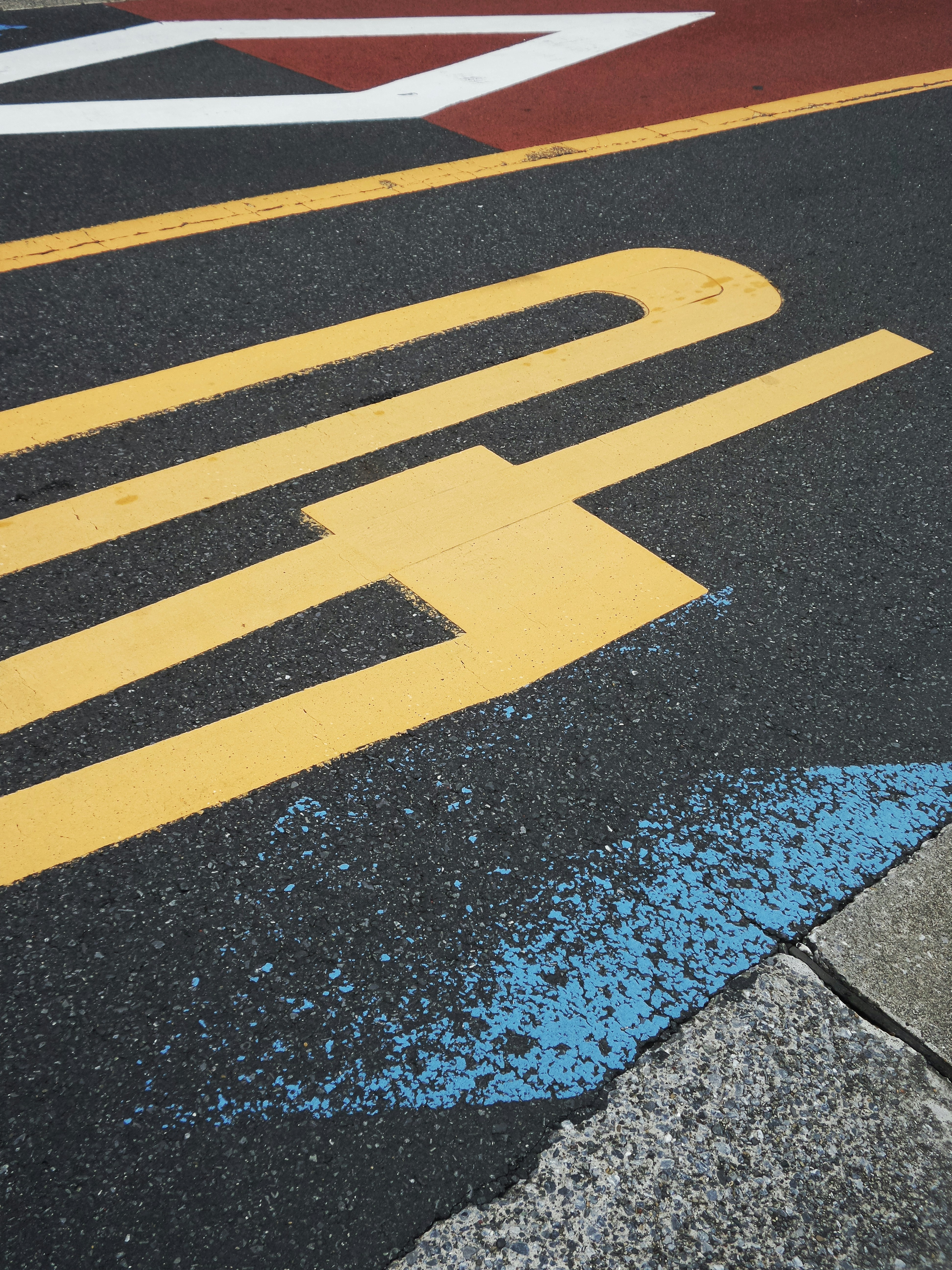 Diagonal Yellow Glyphs on Weathered Asphalt: A Street-Surface Close-Up