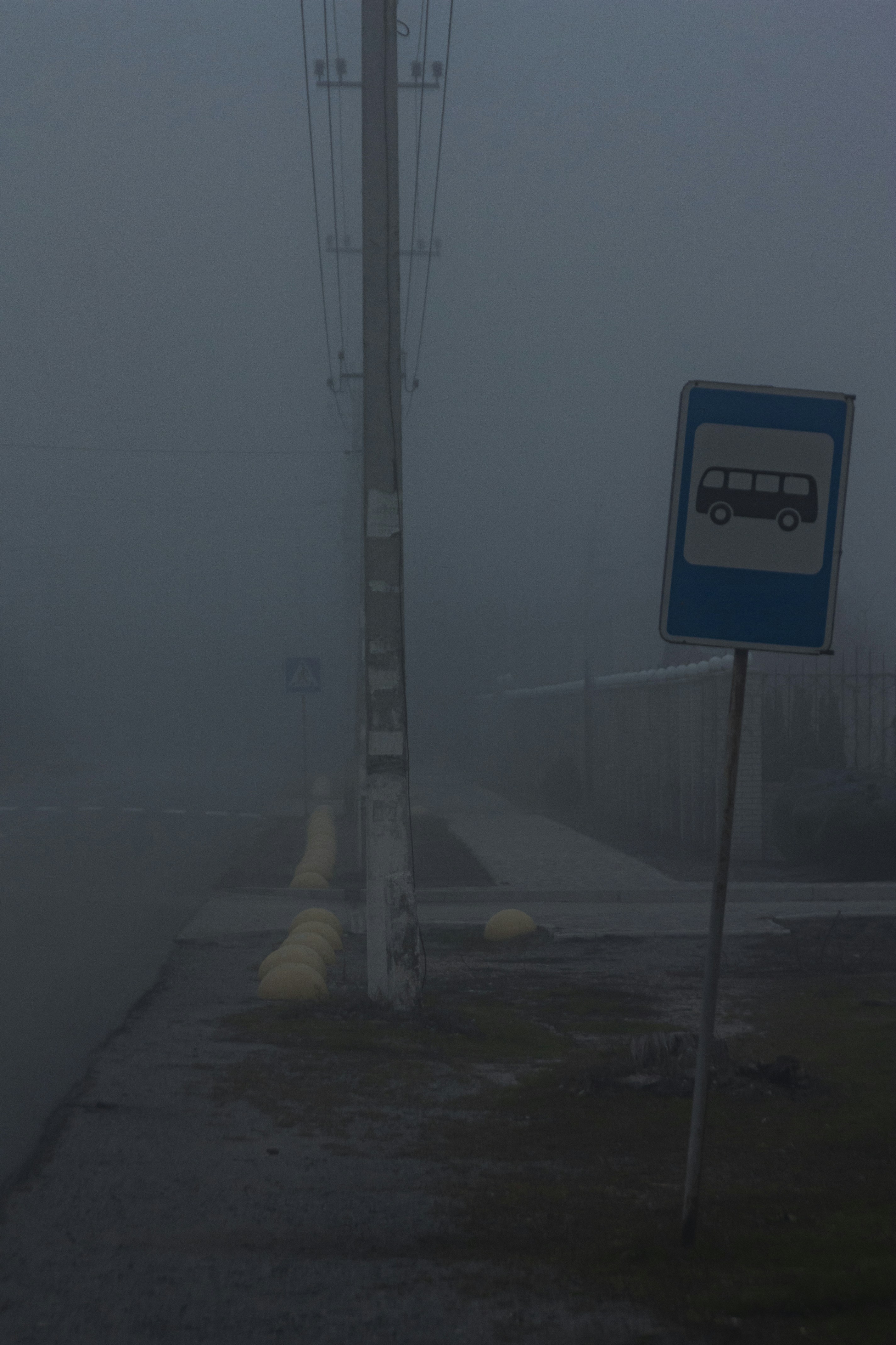 a bus stop sign on a foggy street