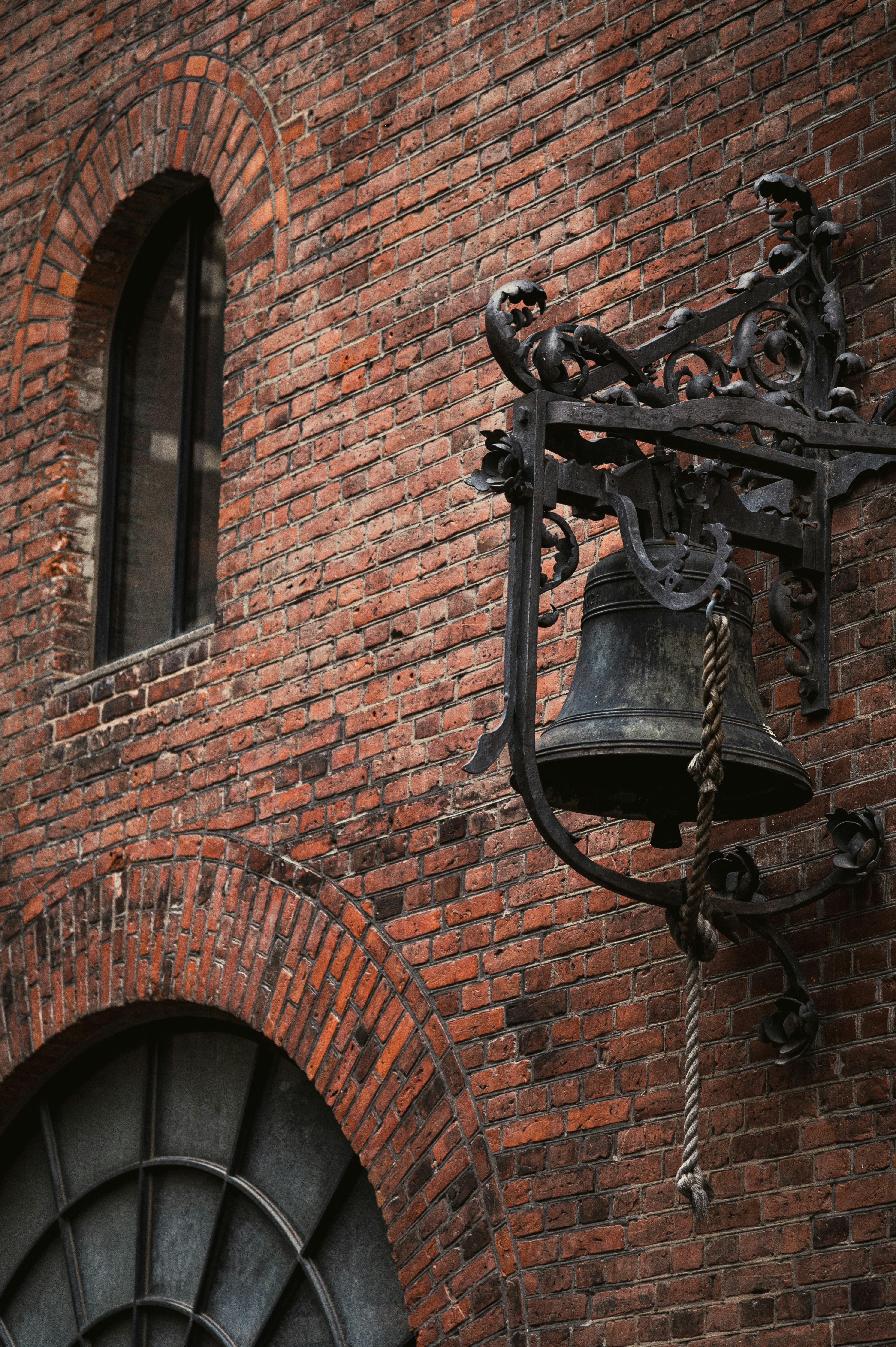 Iron Bell Adorning a Weathered Brick Facade
