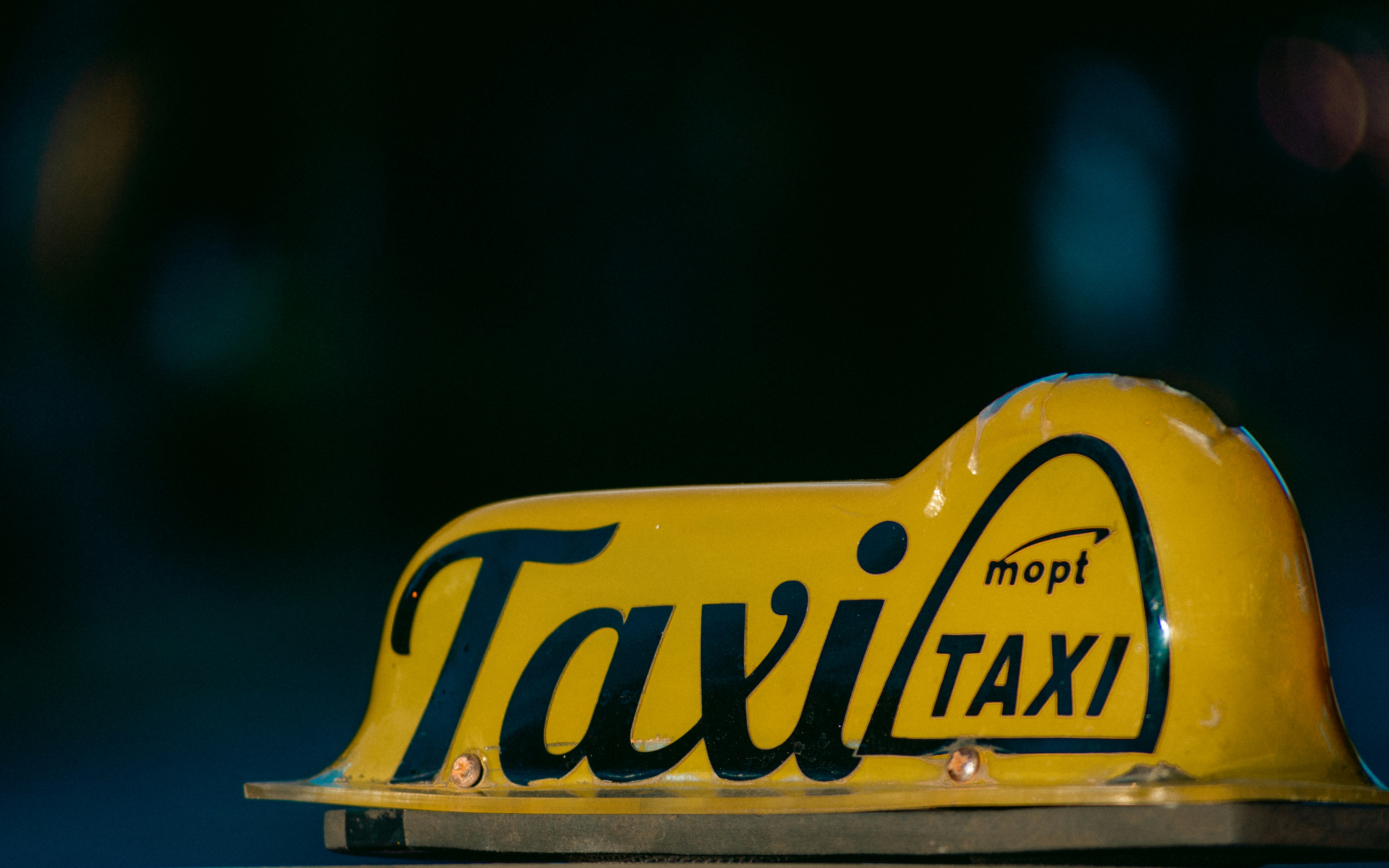 Vibrant yellow taxi sign with bold lettering, showcasing the essential role of taxis in city life.