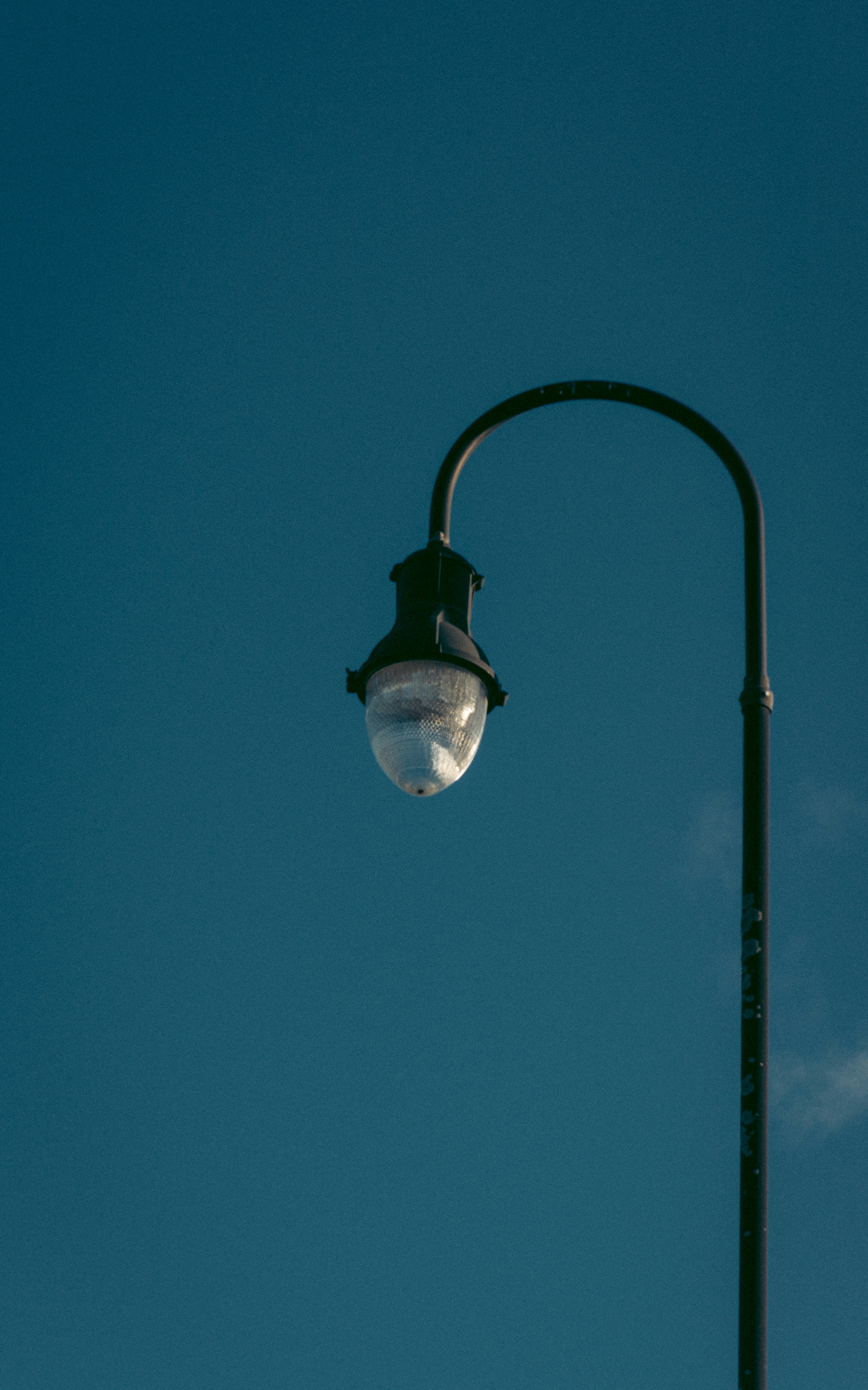 Vintage street lamp silhouetted against a clear blue sky, showcasing its elegant design and functionality.