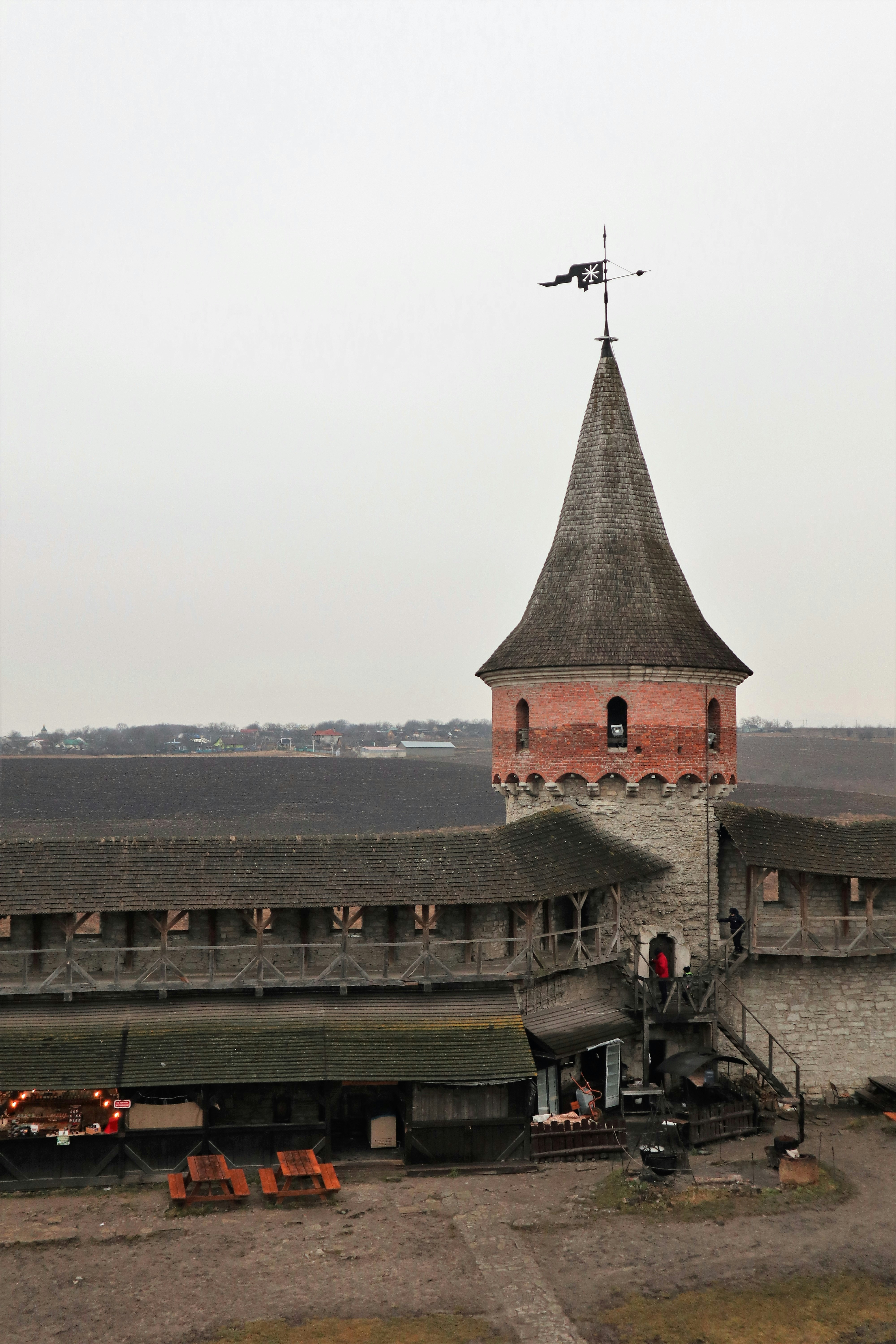 Weathered Turret Over Timbered Fortifications Against a Pale Sky