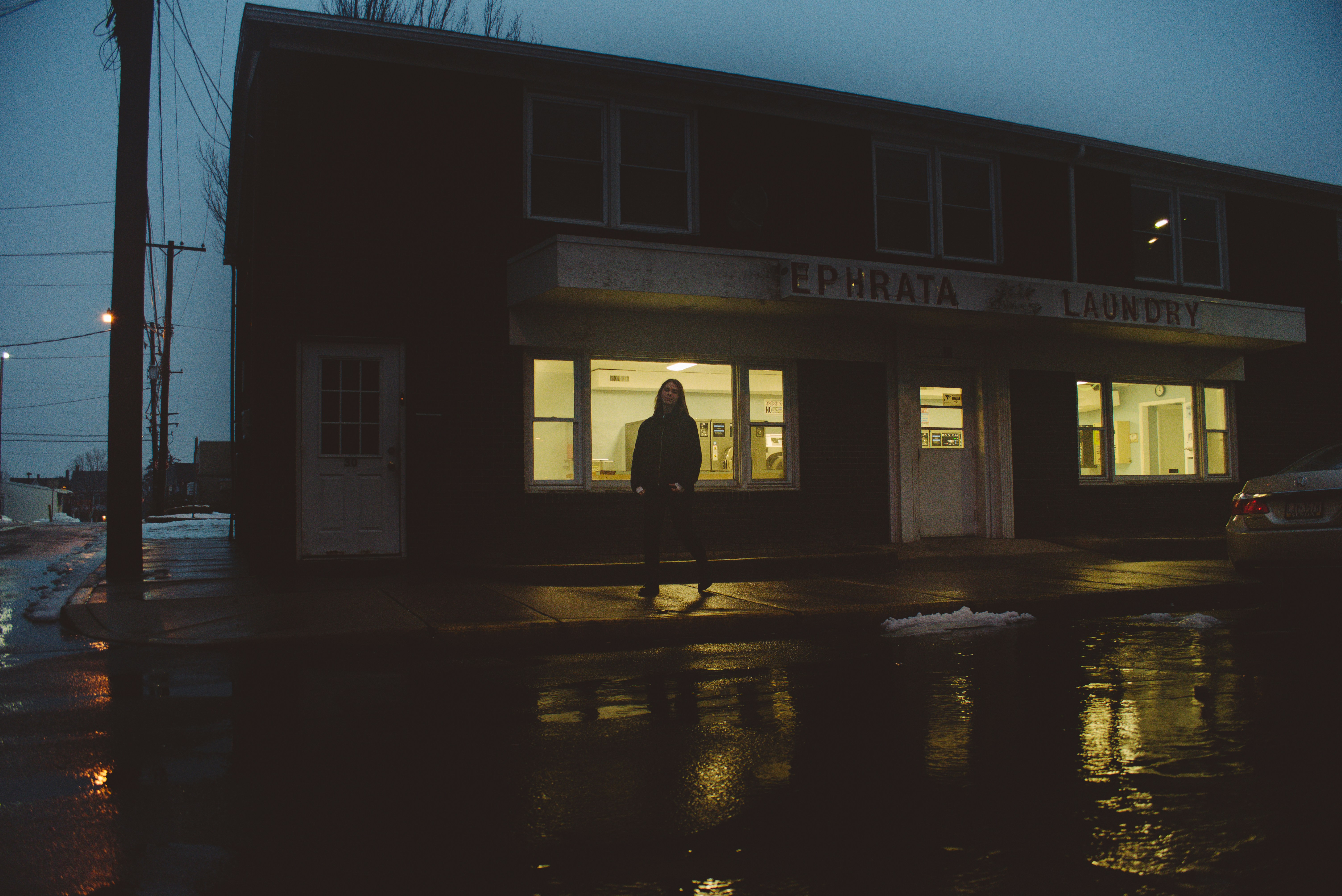 Midnight Threshold: A lone figure by the laundromat window