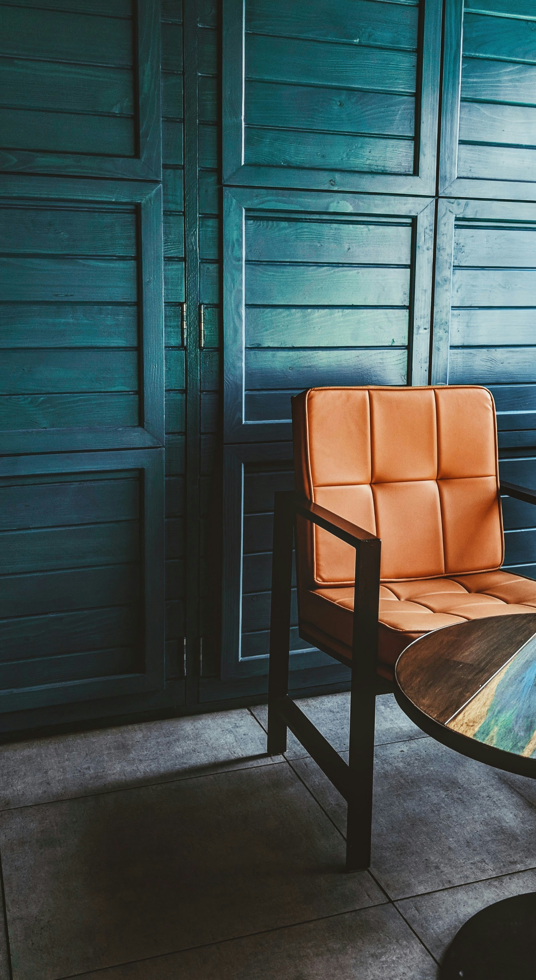 Teal Paneled Quiet: An Orange Leather Chair in a Studio Corner