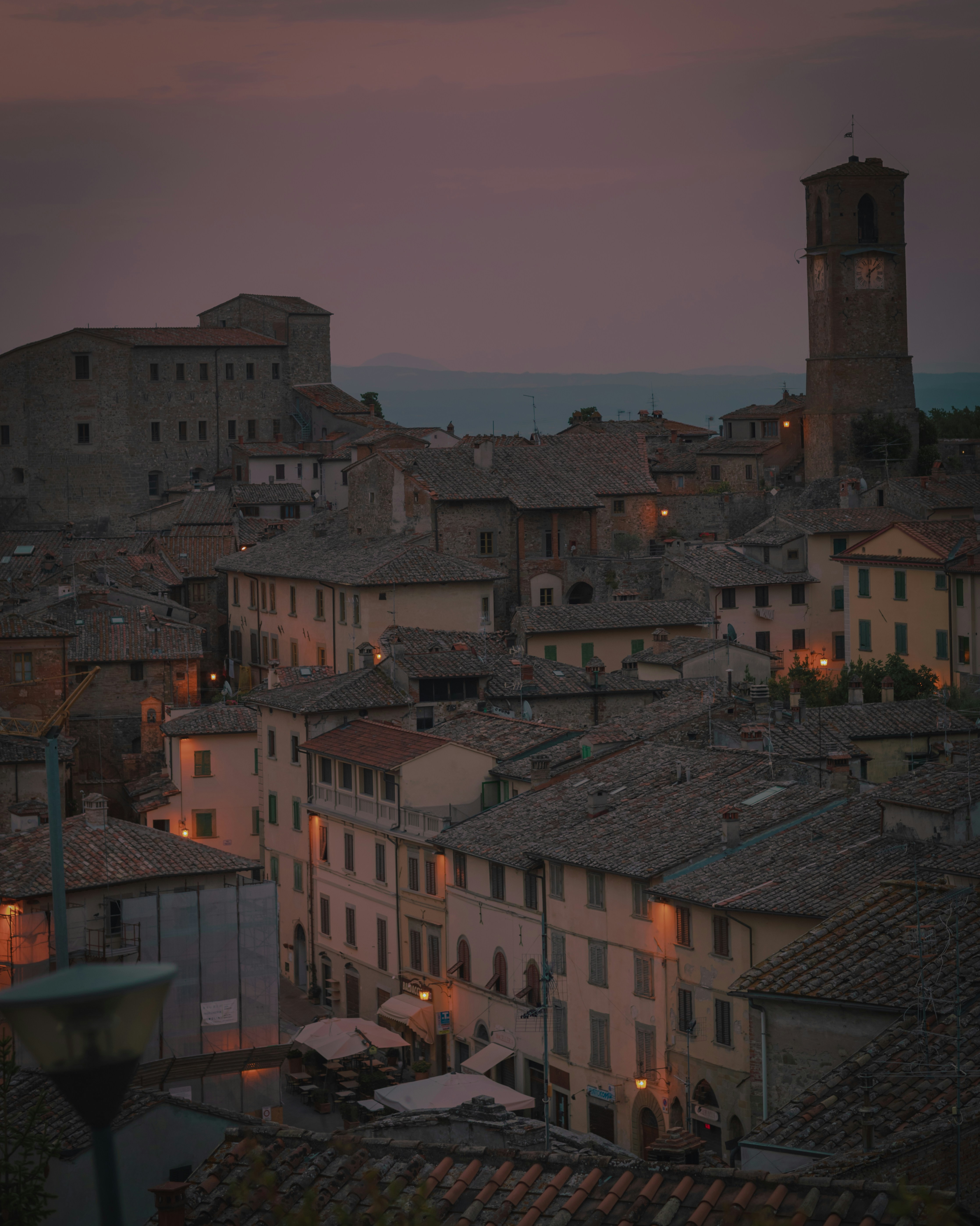 Charming Tuscan village at twilight, showcasing historic architecture and warm streetlights illuminating cobblestone paths.