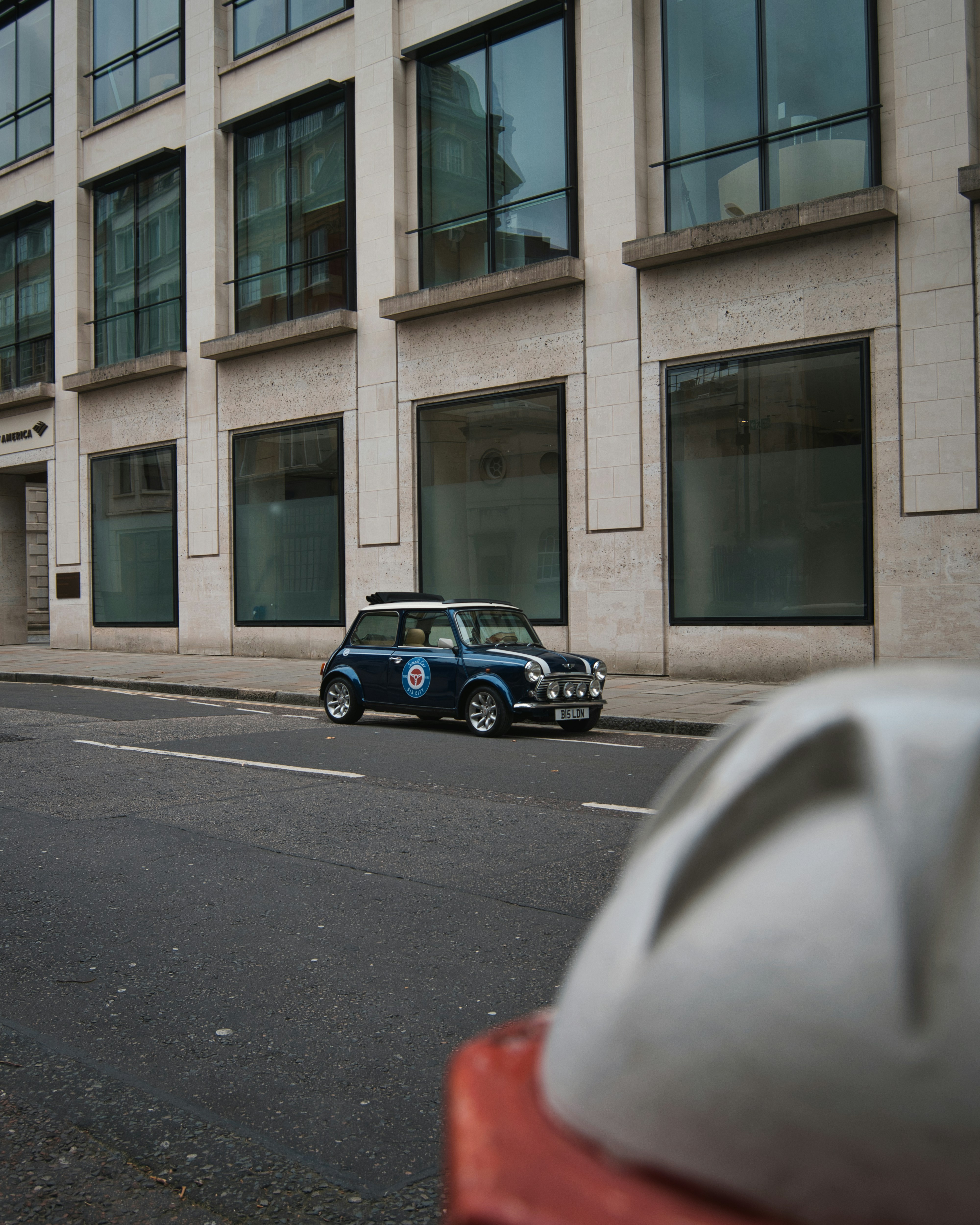 A small blue car parked in front of a tall building photo – Free Car ...