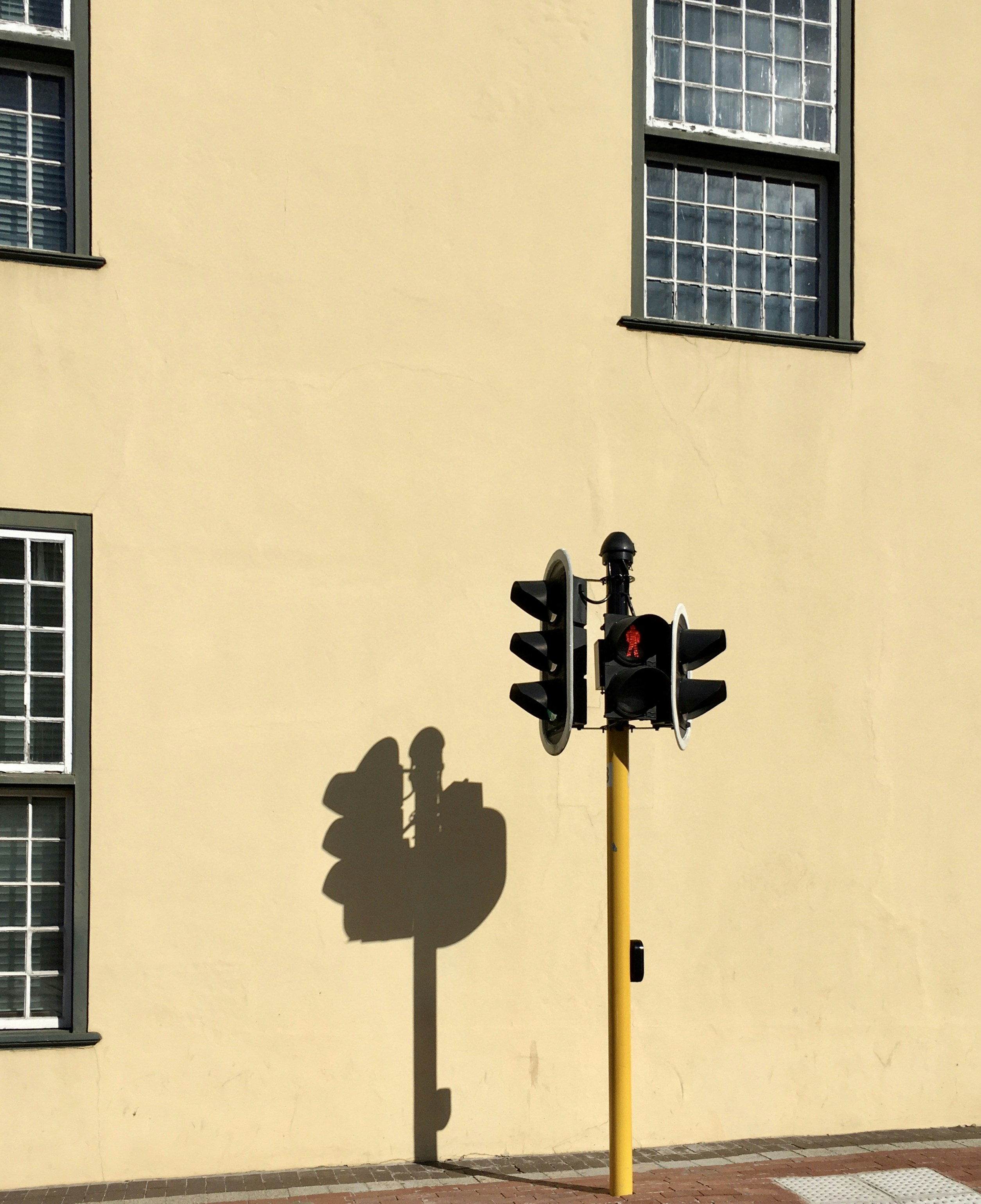 Sunlit Signal and Its Shadow: A Quiet Moment on a Cream Facade