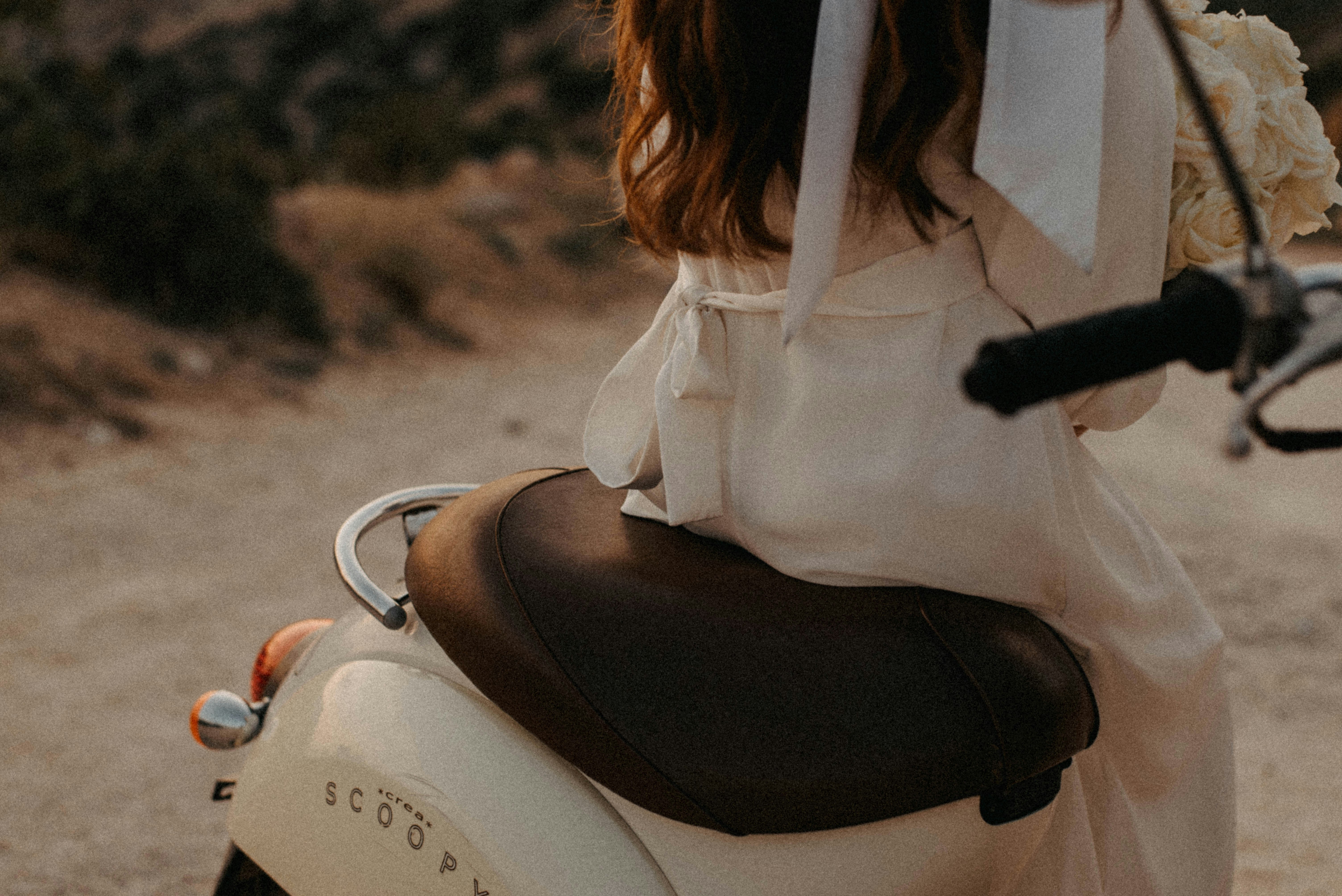 Bridal ride on a vintage cream scooter along a sunlit dusty road