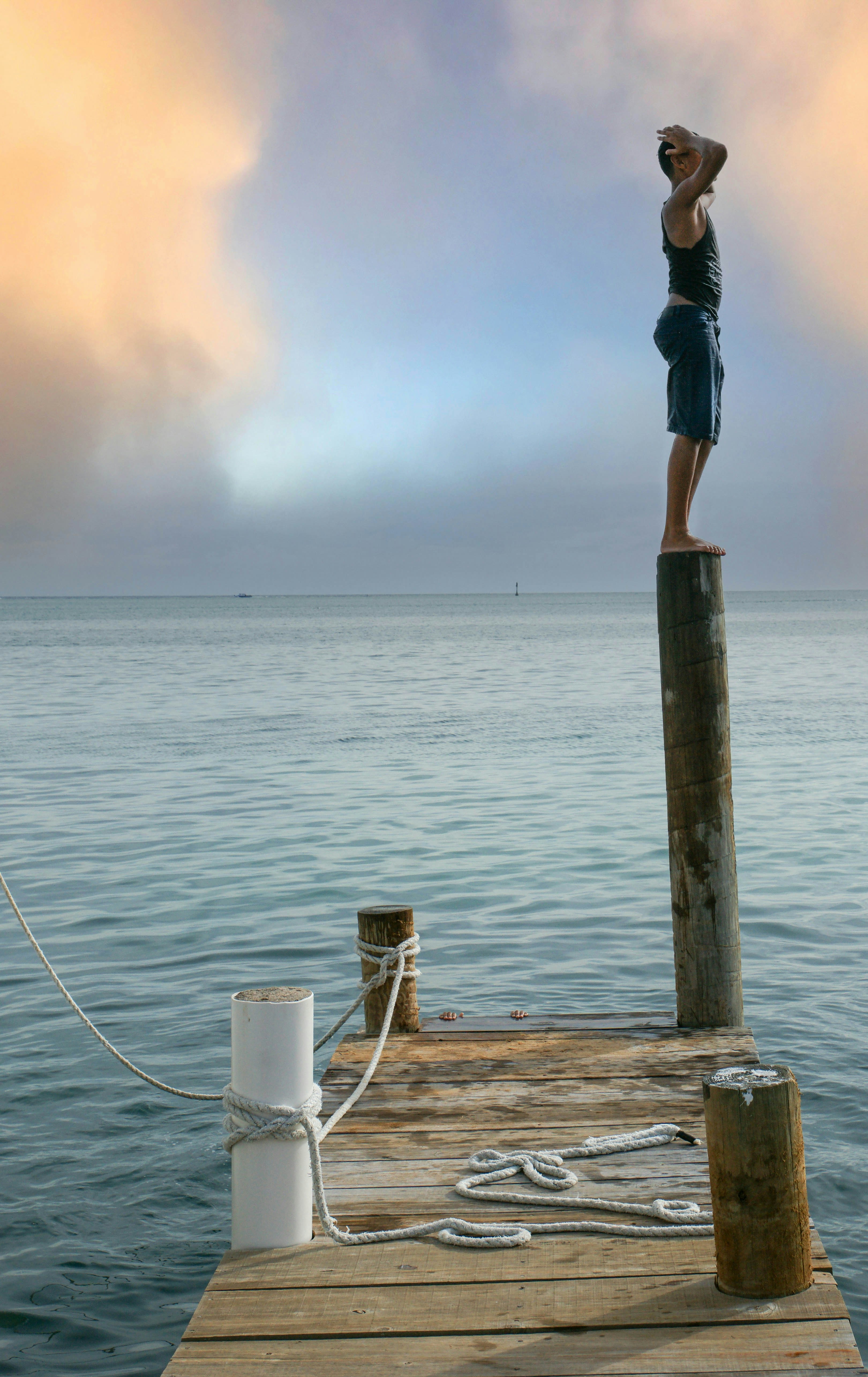 A person standing on a dock with a hat on photo – Free Water Image on ...