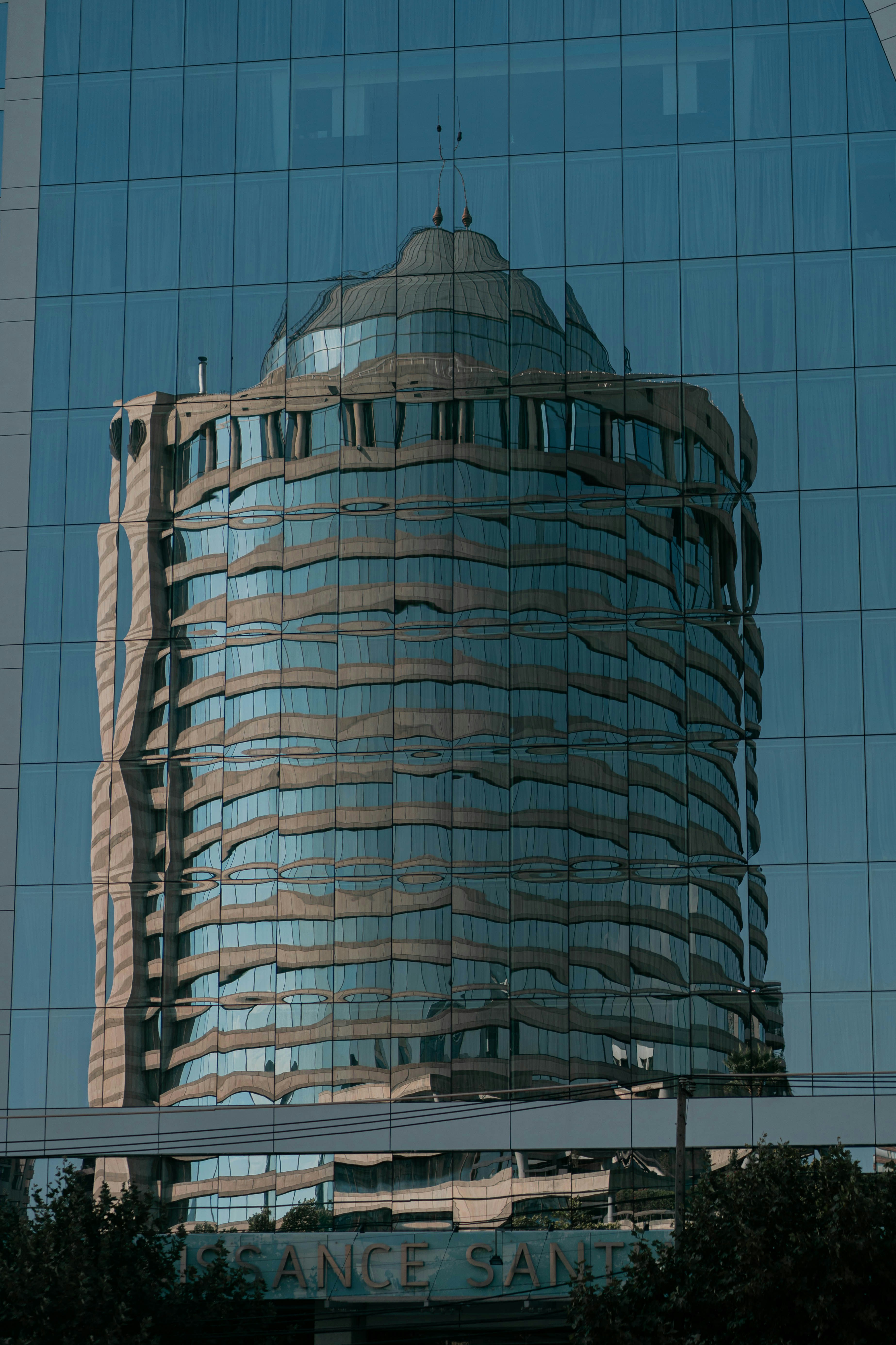 a large glass building with a clock on it's side